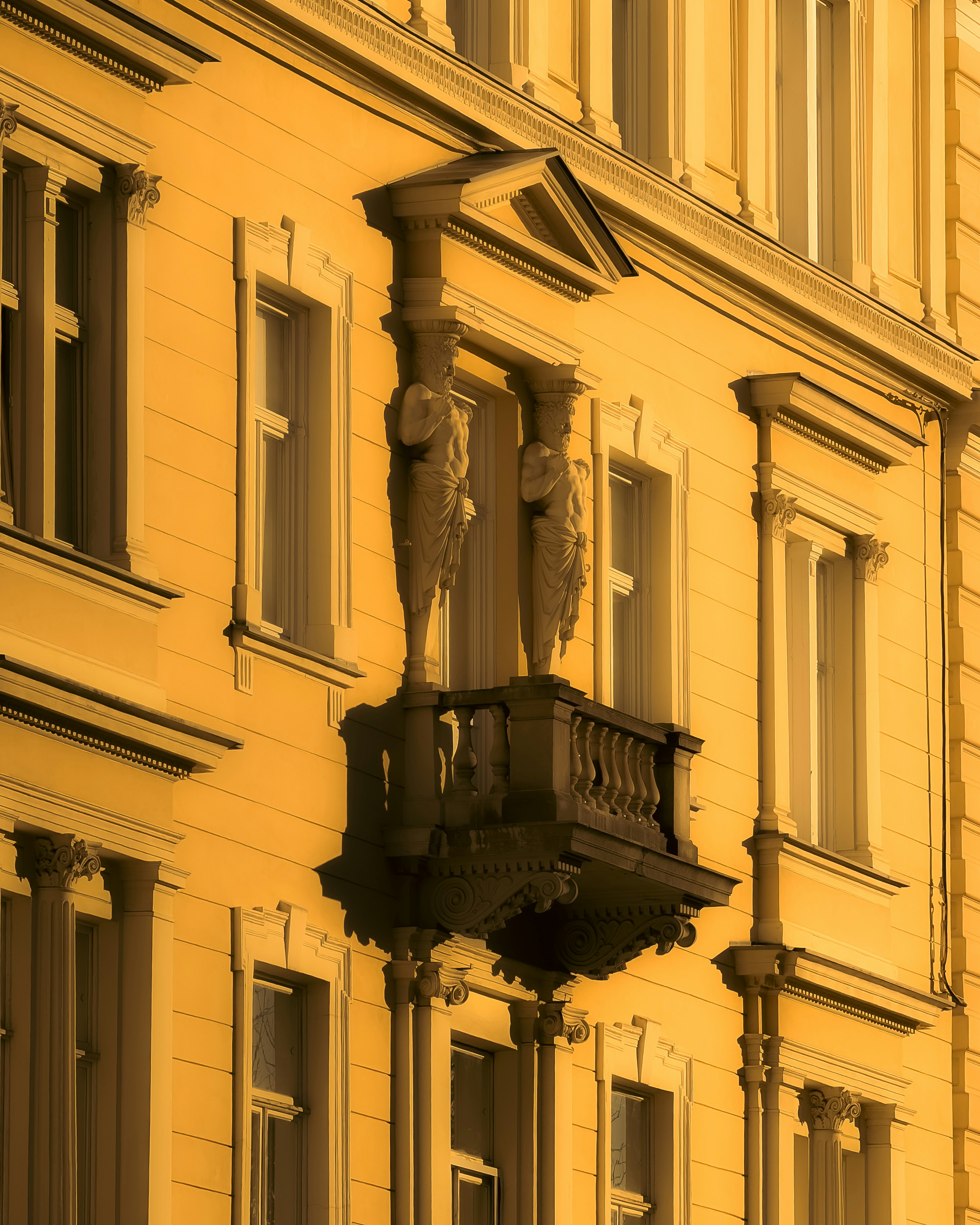 Golden Facade: Balcony Statues in Warm Light