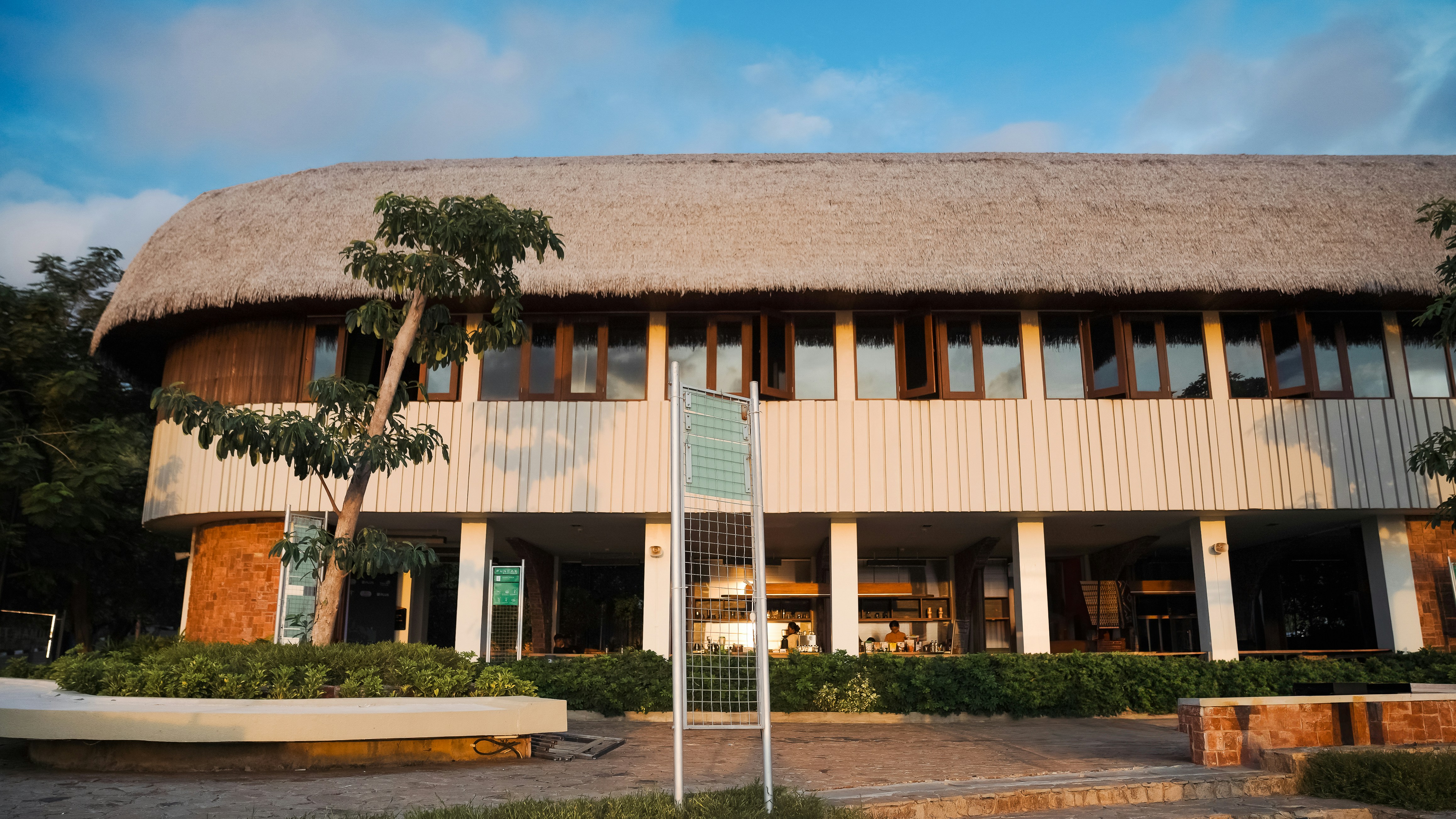 Thatched-Roof Campus Facade Framed by Tall Trees