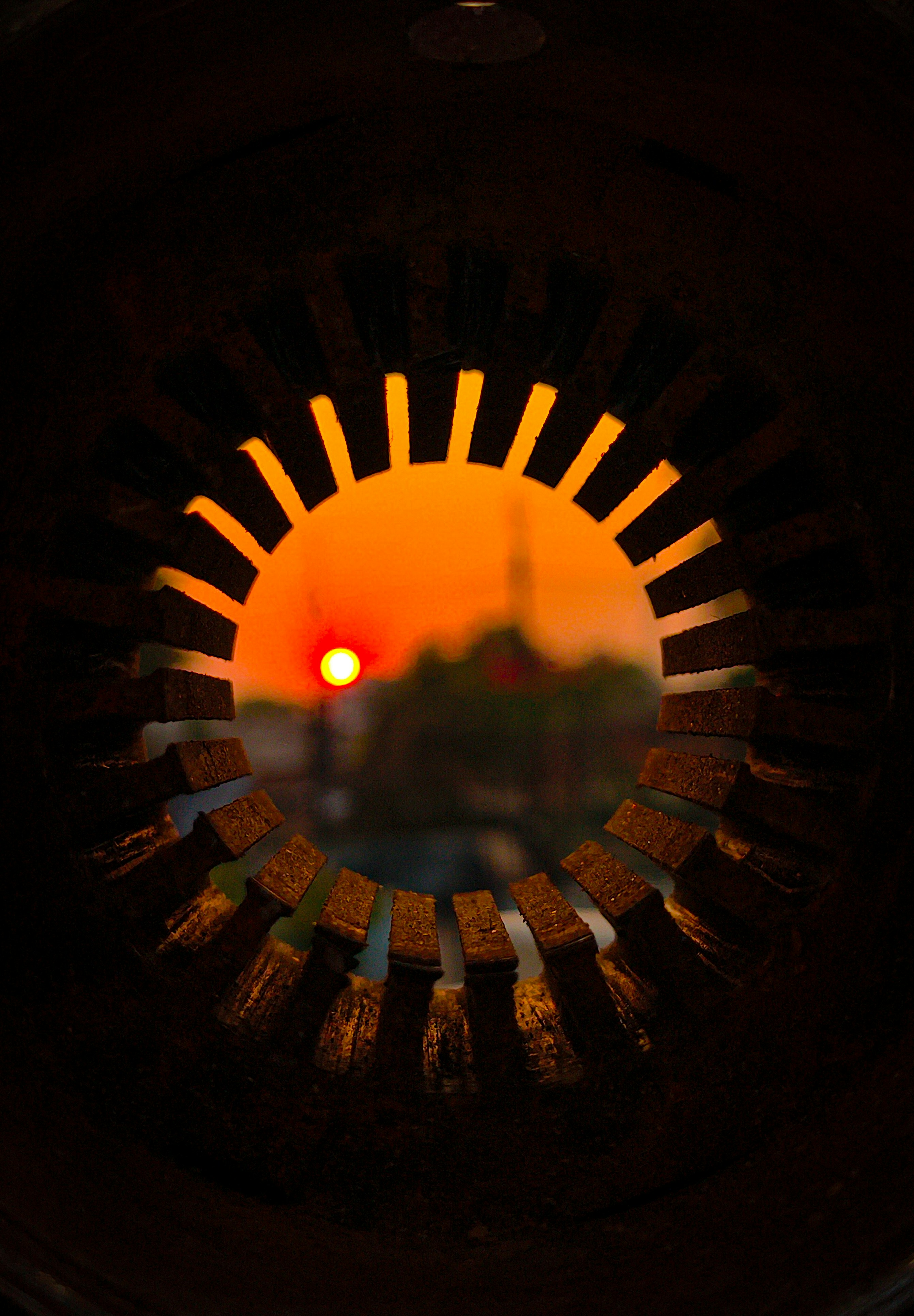 Sunset through a ring: urban pulse framed by iron spokes