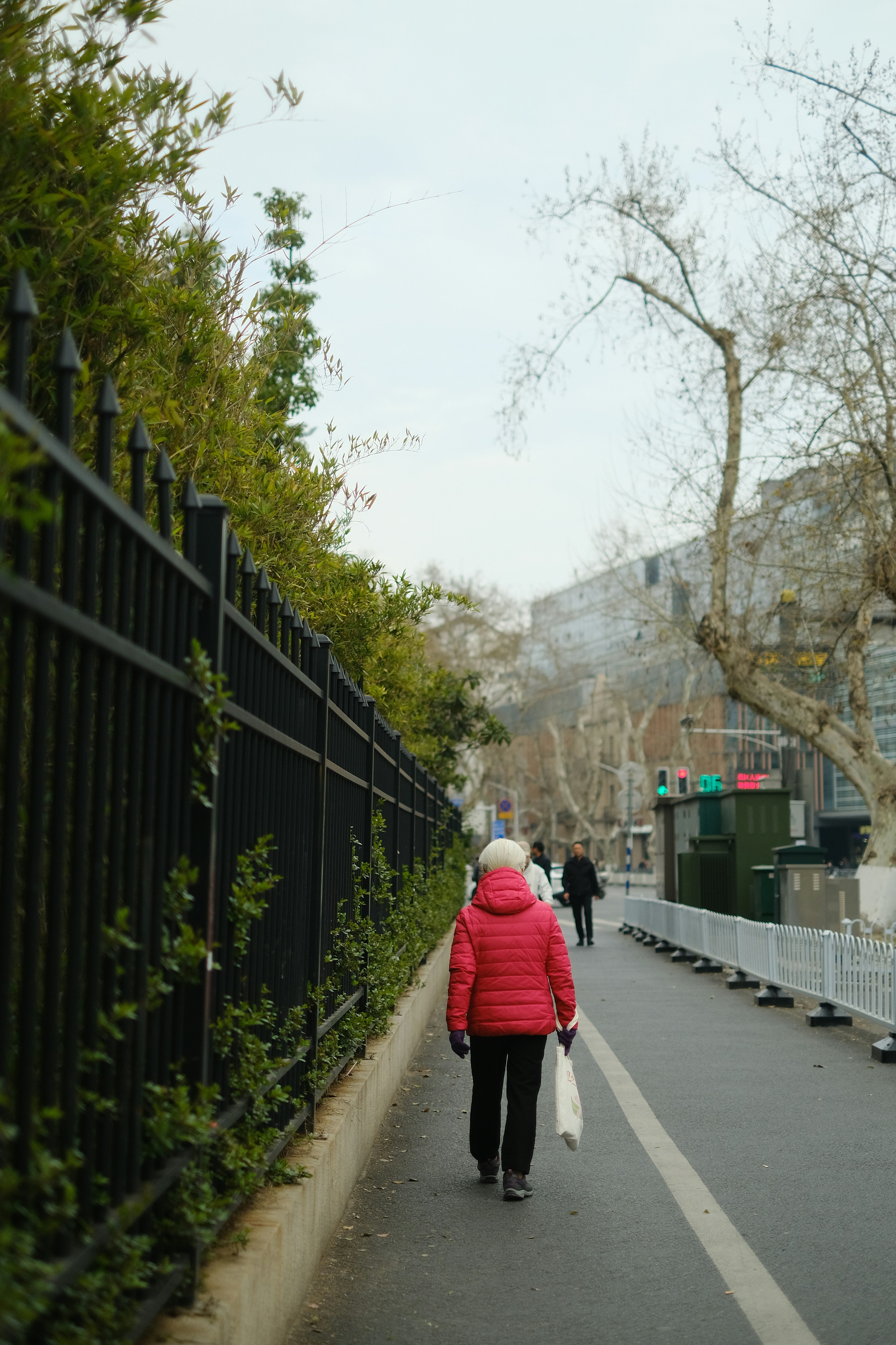 A lone rider in a red jacket walks the urban riverside path