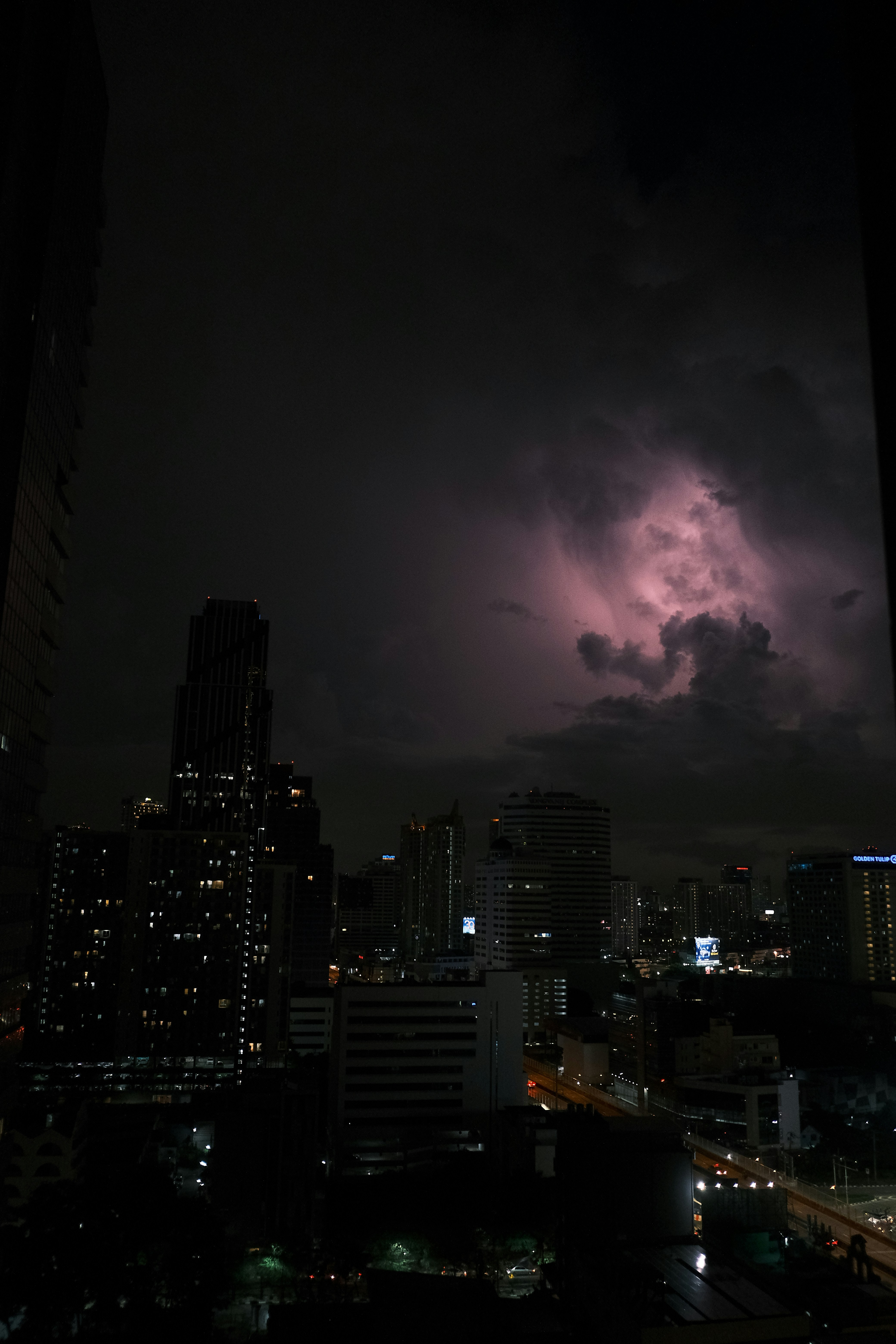 Nightfall Thunder: City Lights Meet a Pink-Cored Cloud
