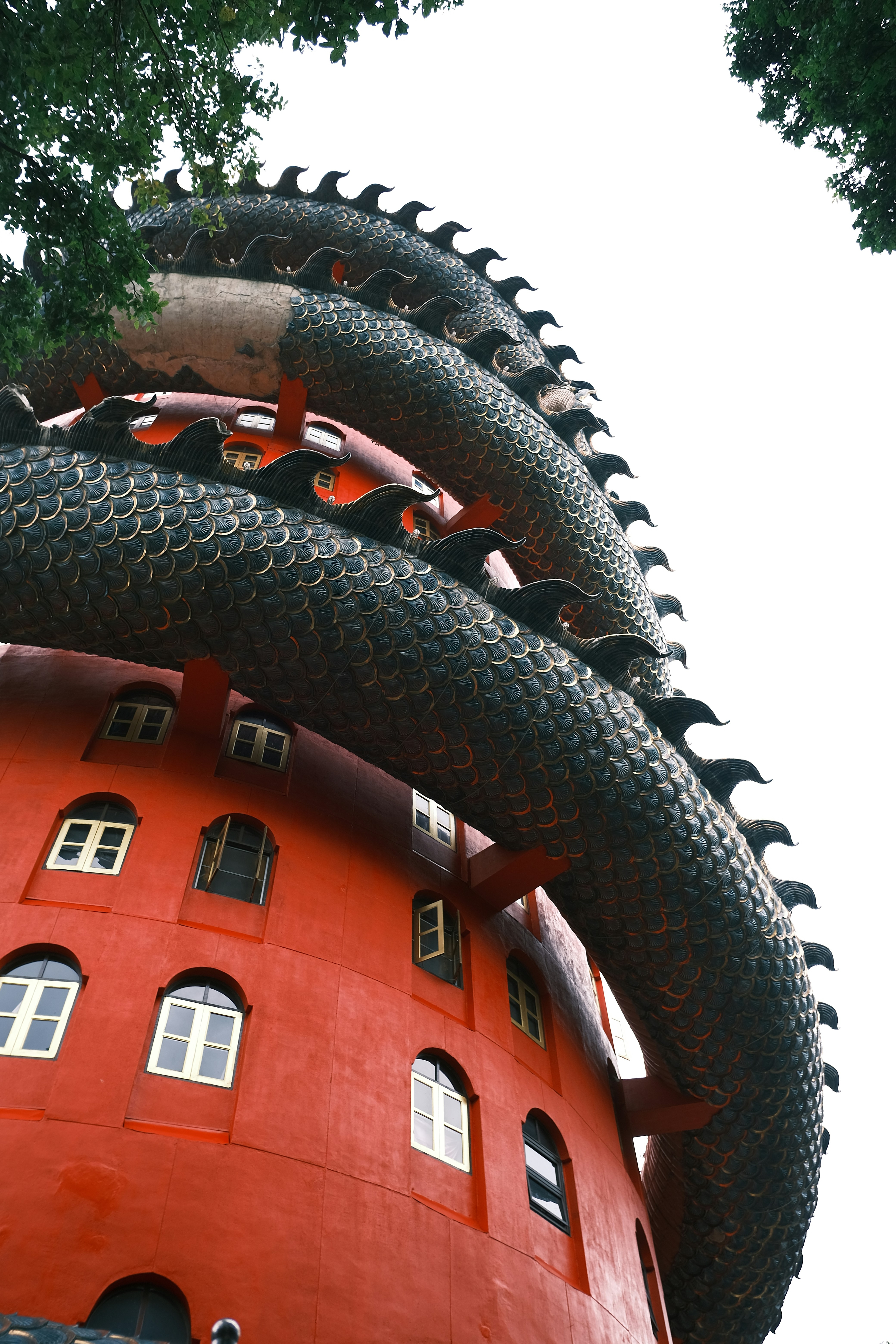 Coiled Guardians: A Red Structure Curling Beneath Kilns of Steel