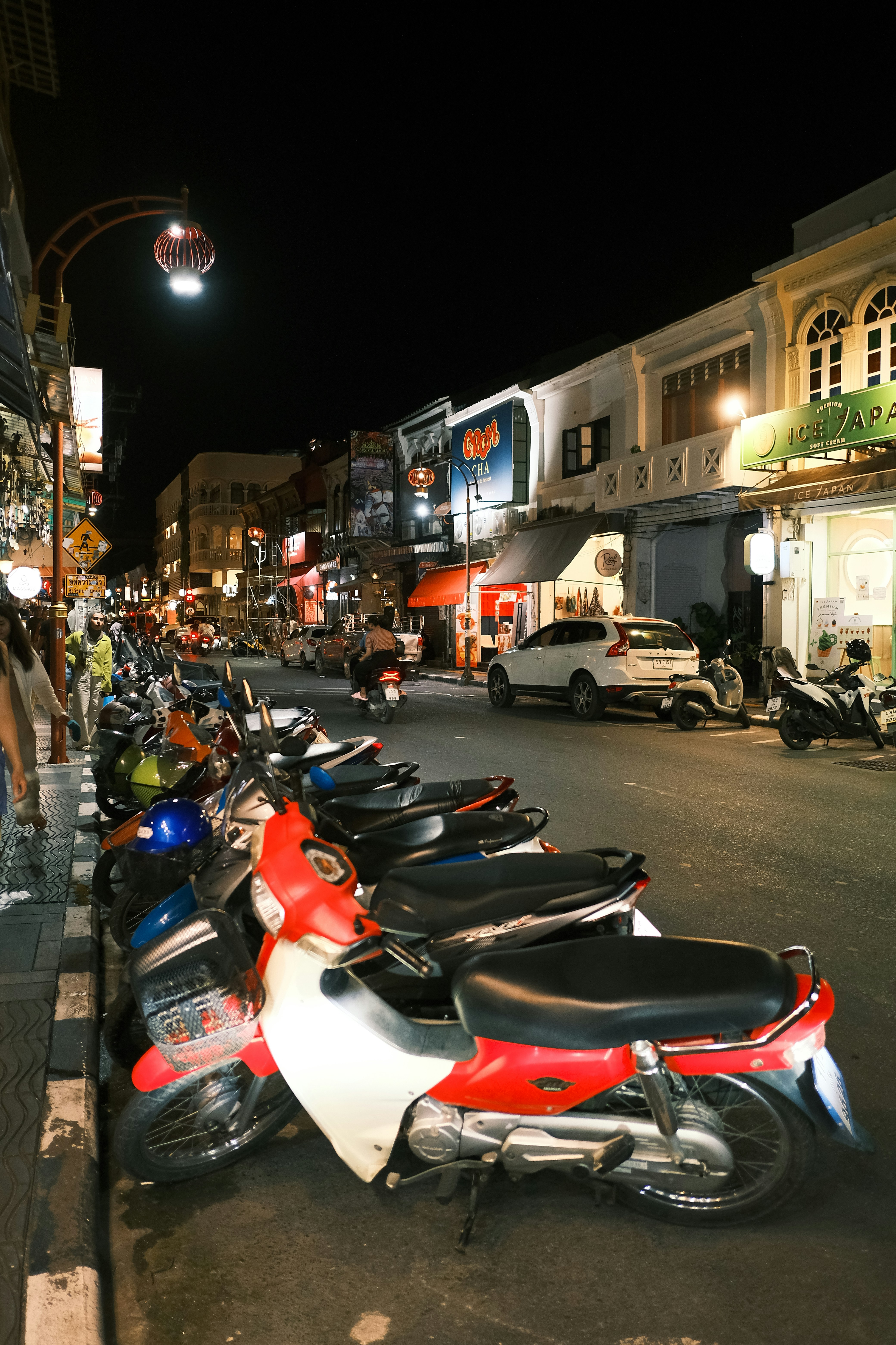 Line of Colorful Scooters under Night Streetlights