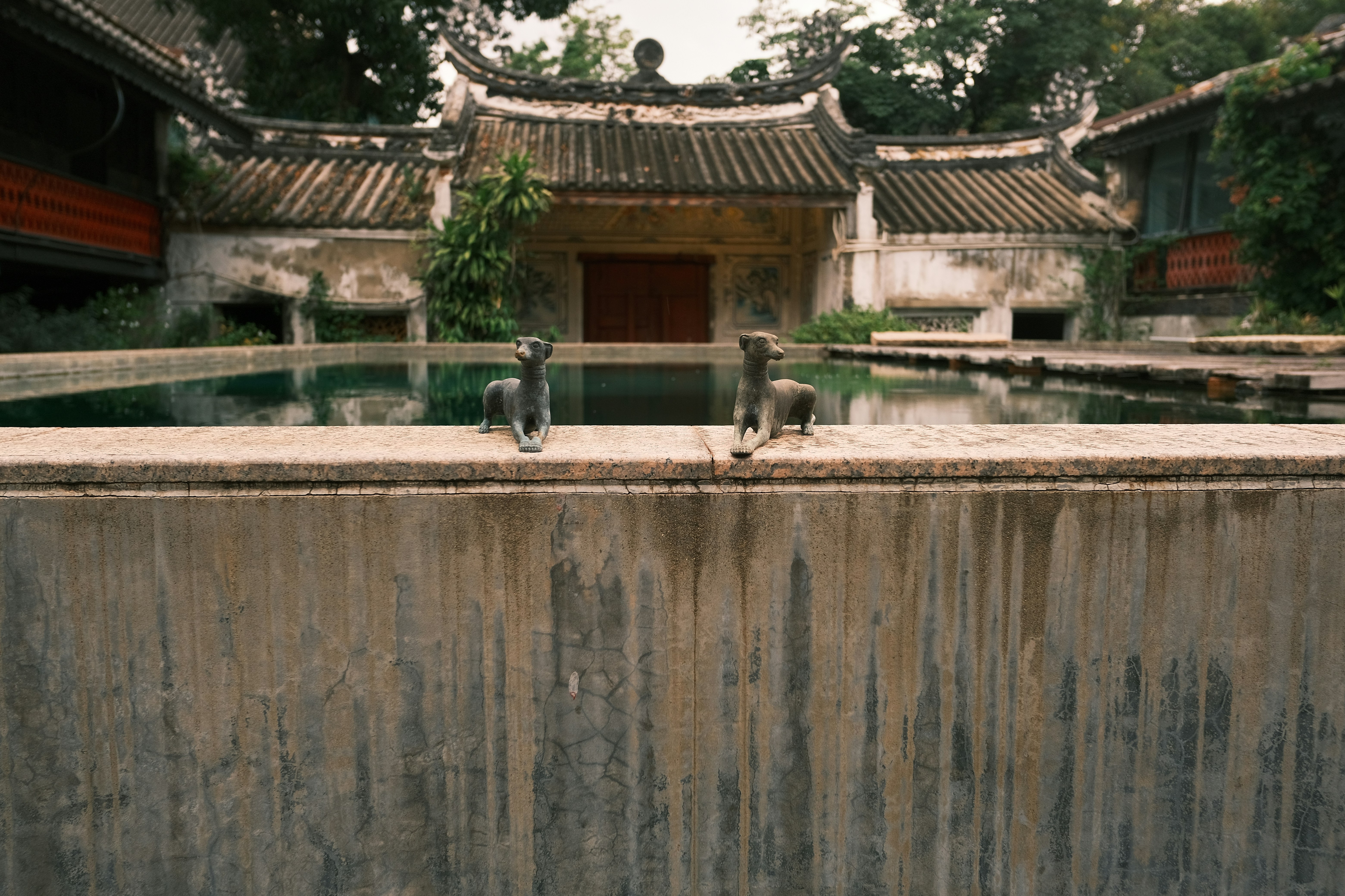 Toothy Courtyard Guardians: Weathered Faucets Framing a Quiet Pond