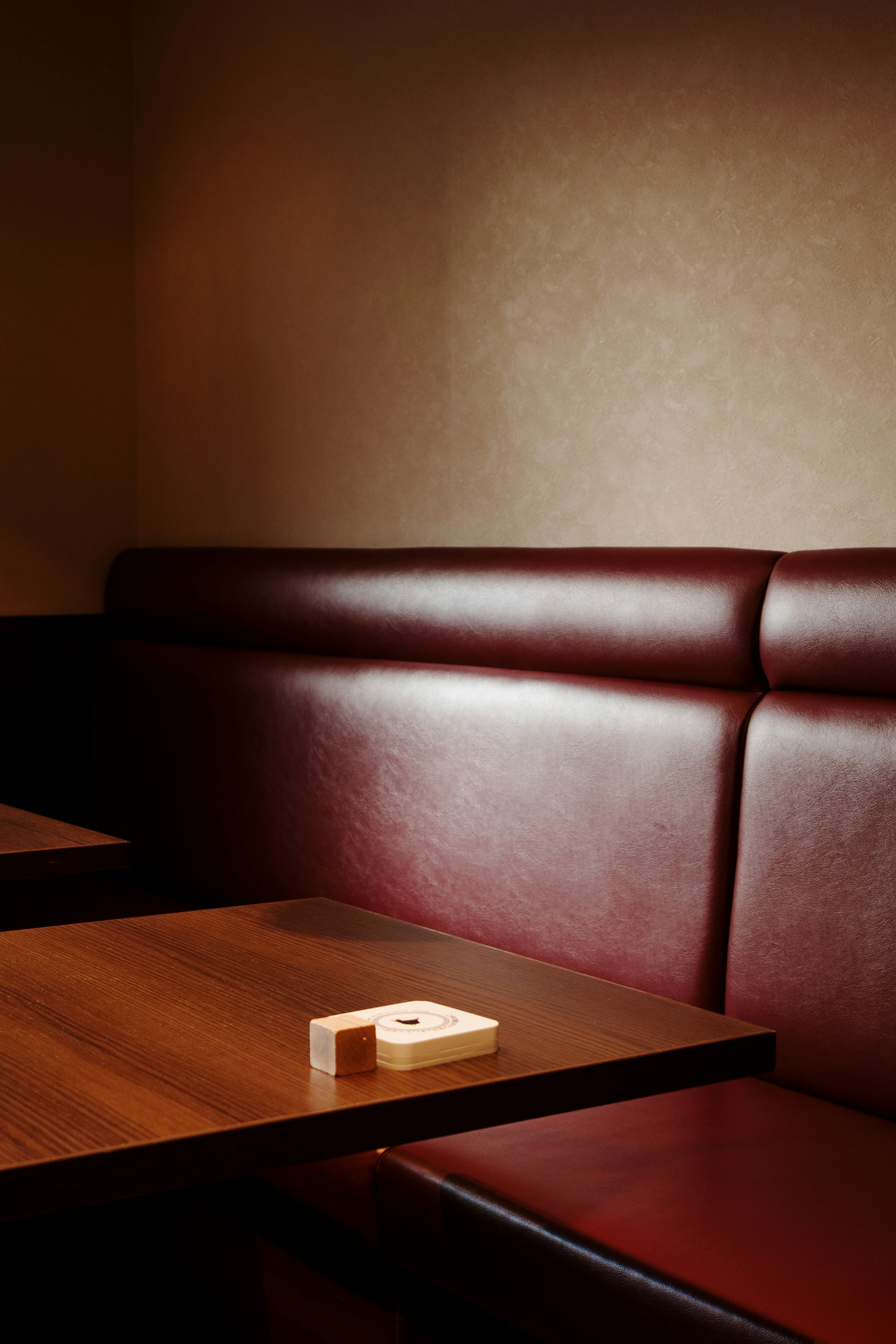 Dim Lounge Corner: Leather Booth and a Tiny Card On Wood Table