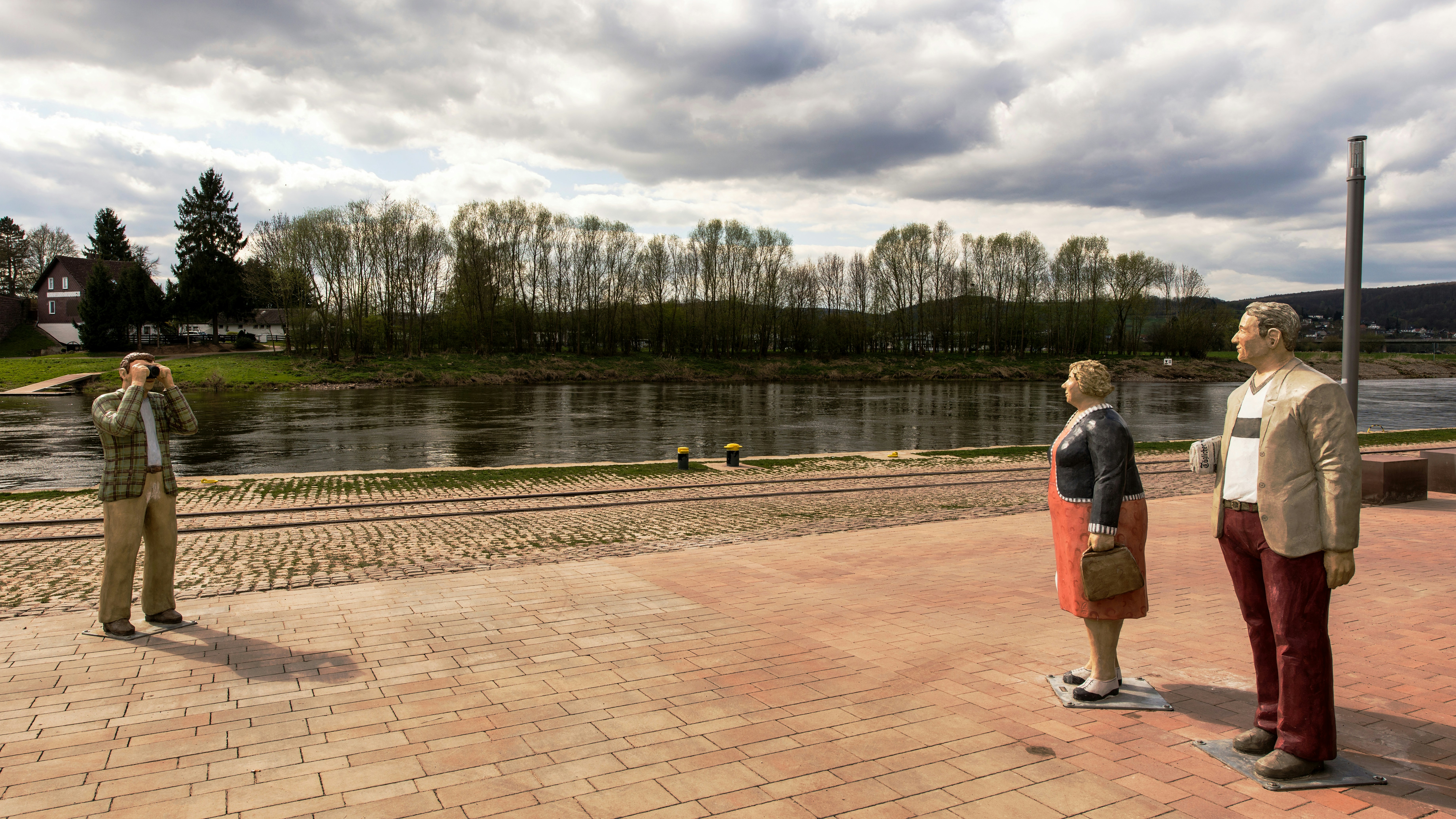 Riverfront Portrait: Tourists on a Brick Promenade with the Waterway in Reach