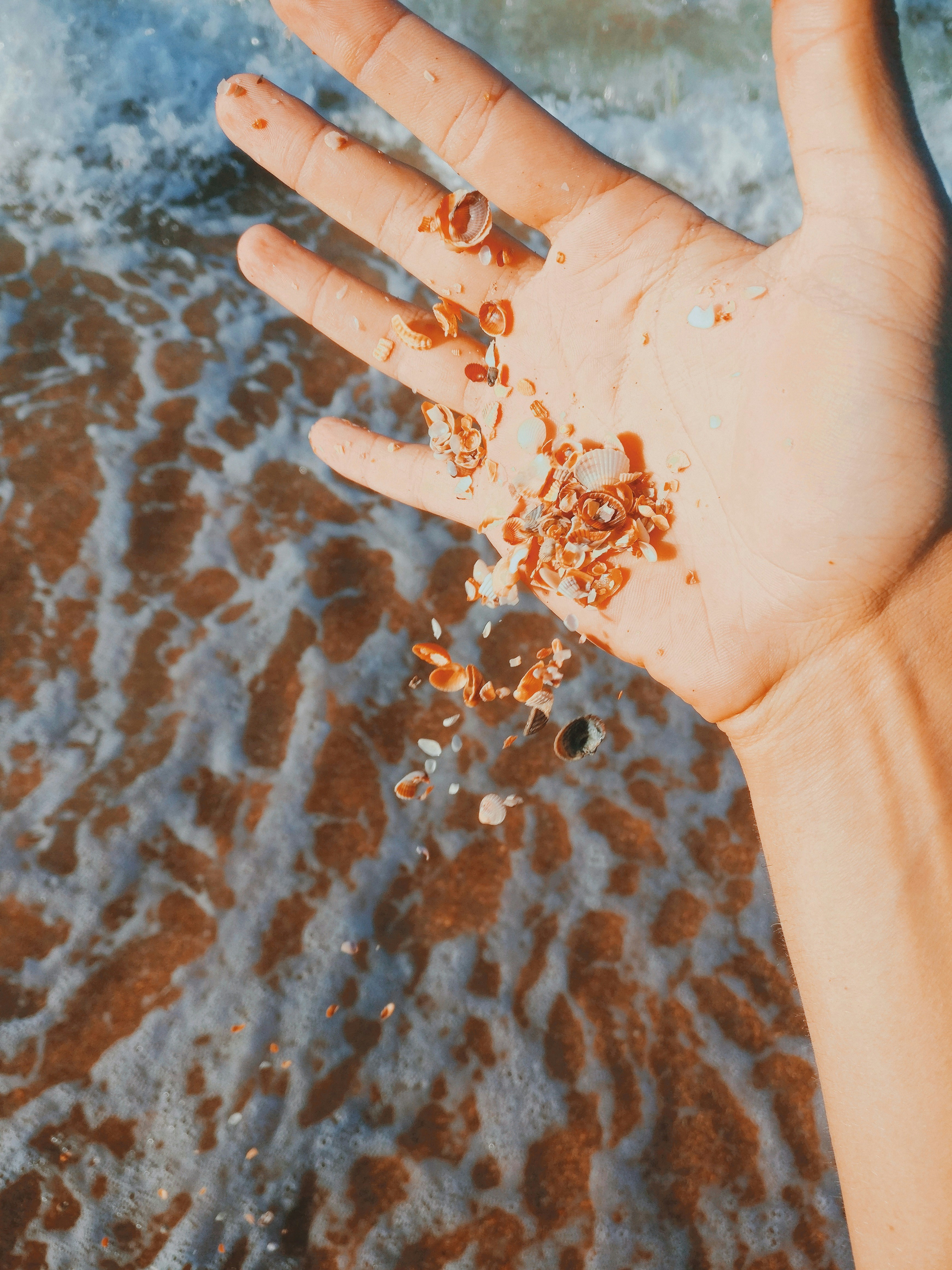 Hand in Water: Pink Sand Grains Cascading from a Splashing Palm