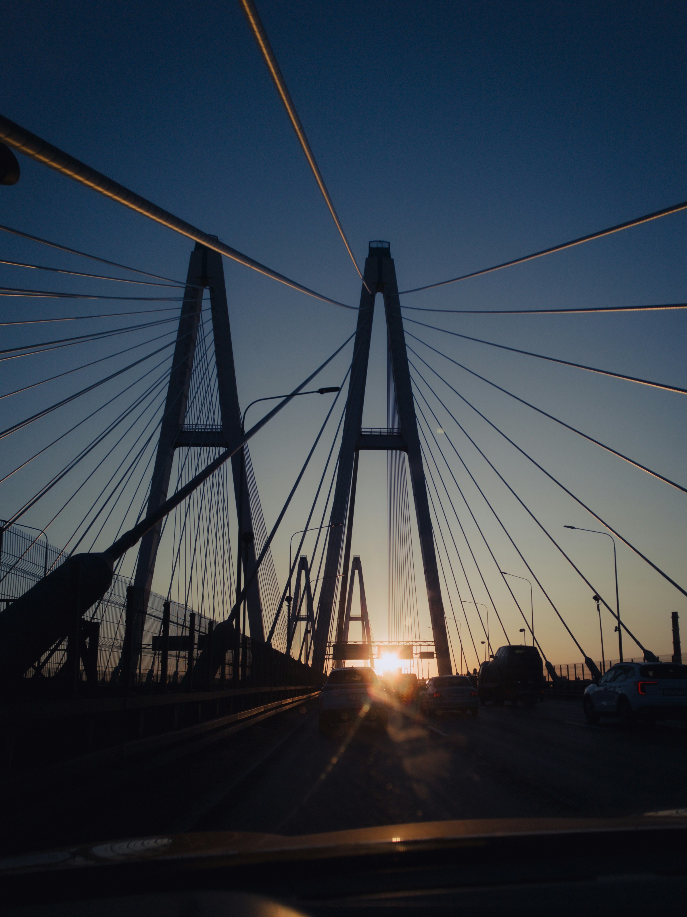 Sunset Over a Cable-Stayed Bridge: Car Lights and Long Shadows