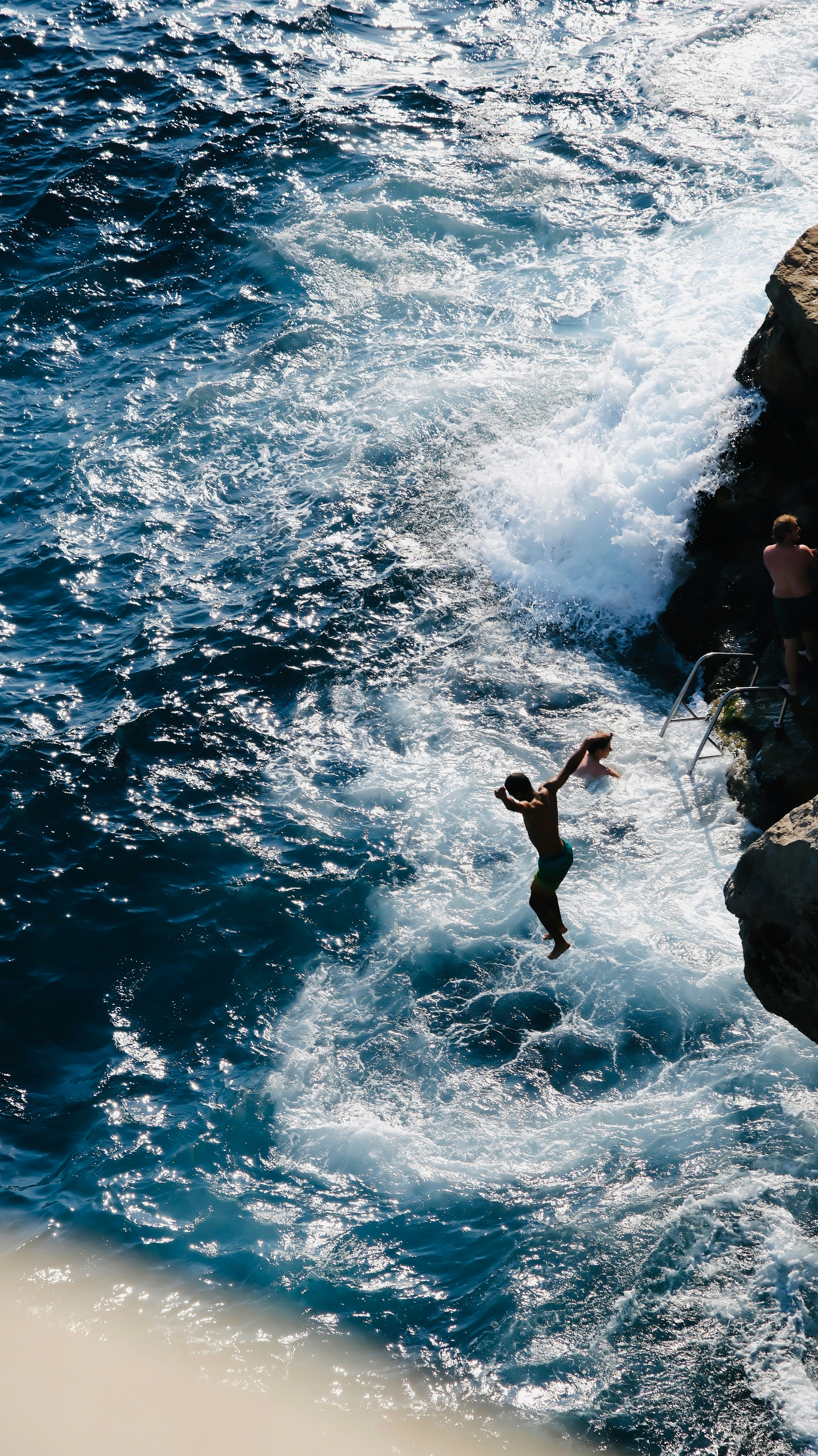 Leap of Splash: A Diver Drops into Blue Foam from Coastal Rocks