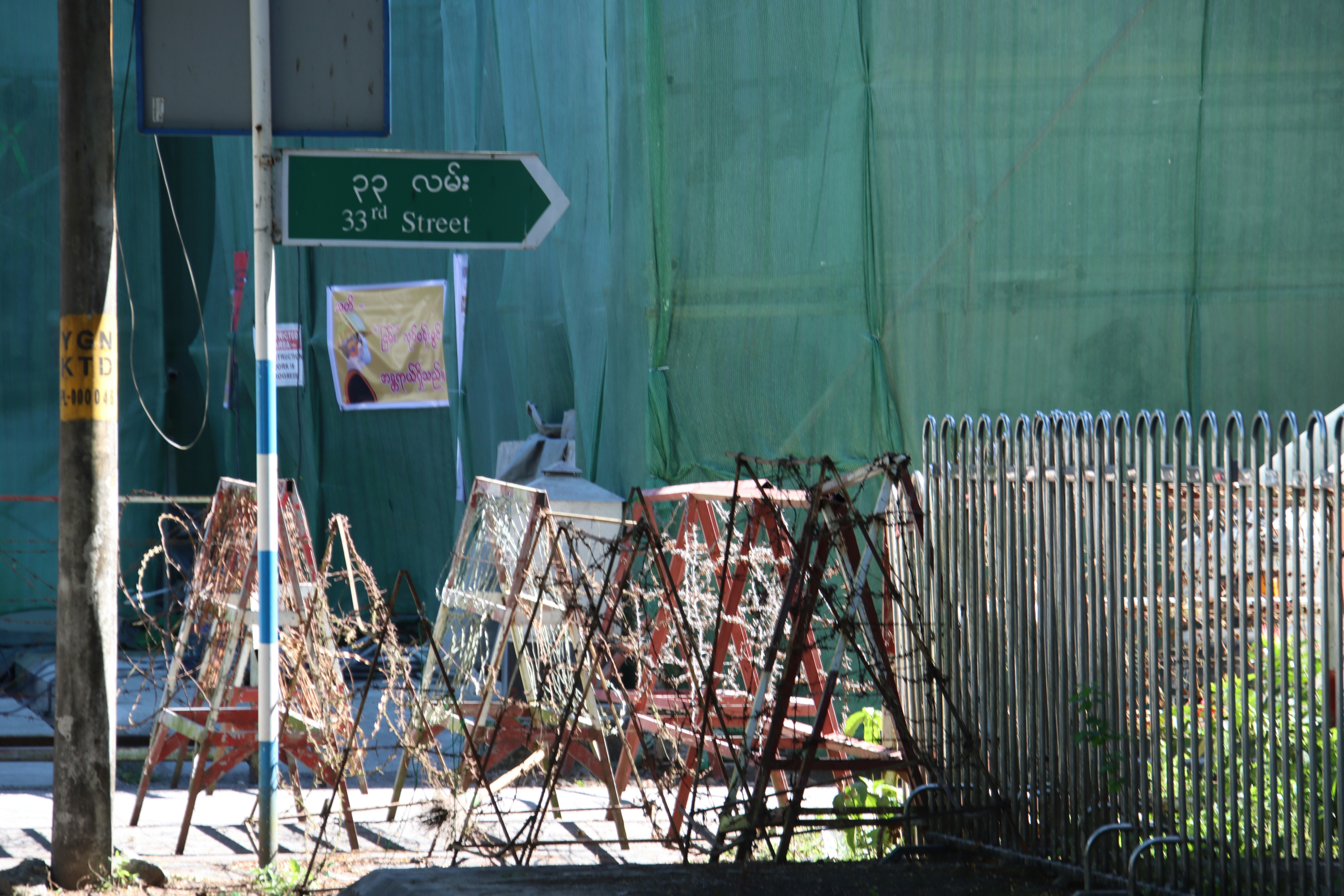 Signpost and construction barriers on a sunlit urban corner