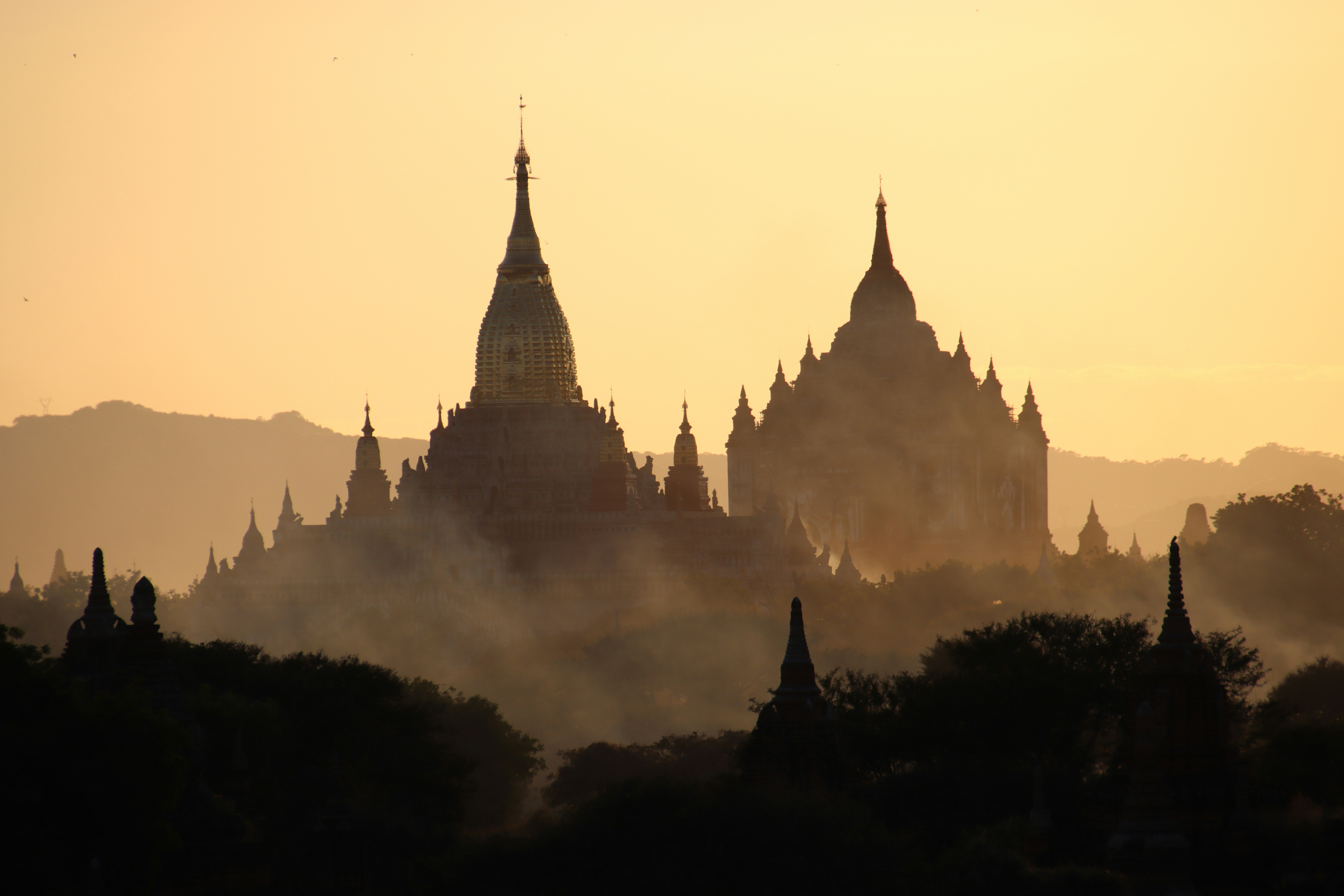 Silhouetted Temples at Daybreak Over Misty Forest
