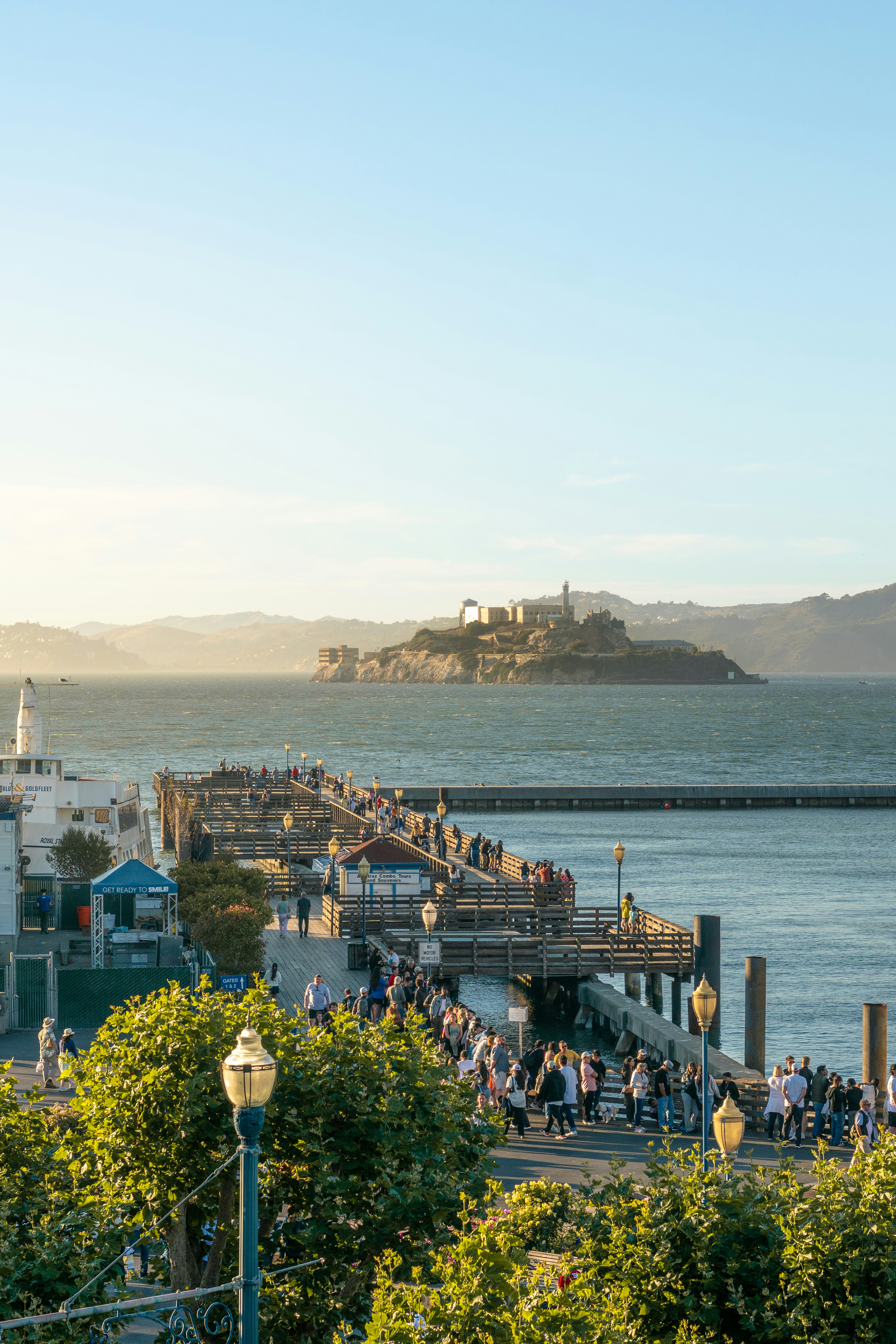 People Walk the Pier Toward an Island Fortress at Sunset