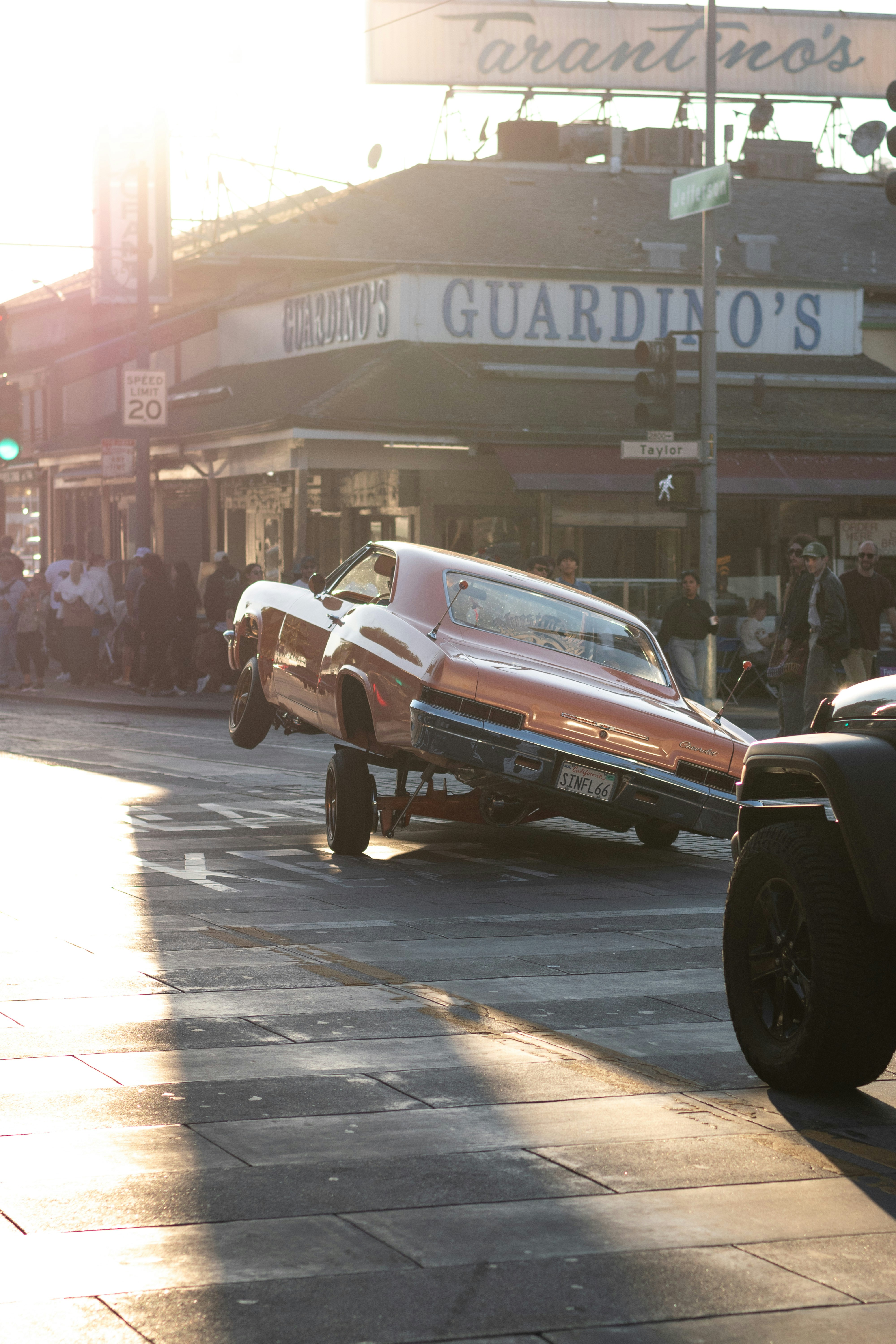 Classic car doing a wheelie on city street