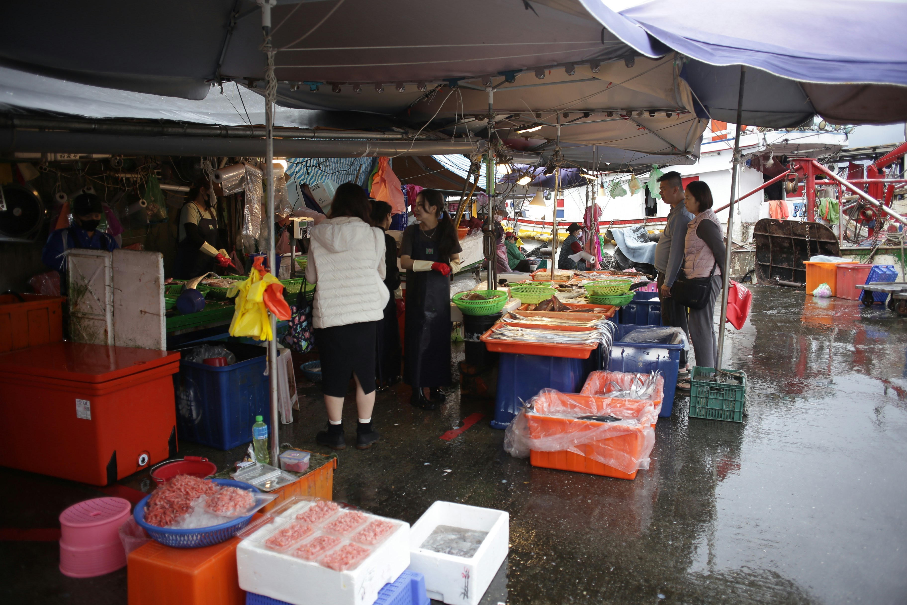 Market Under Rain: Vendors and Customers Around Fresh Seafood Stalls
