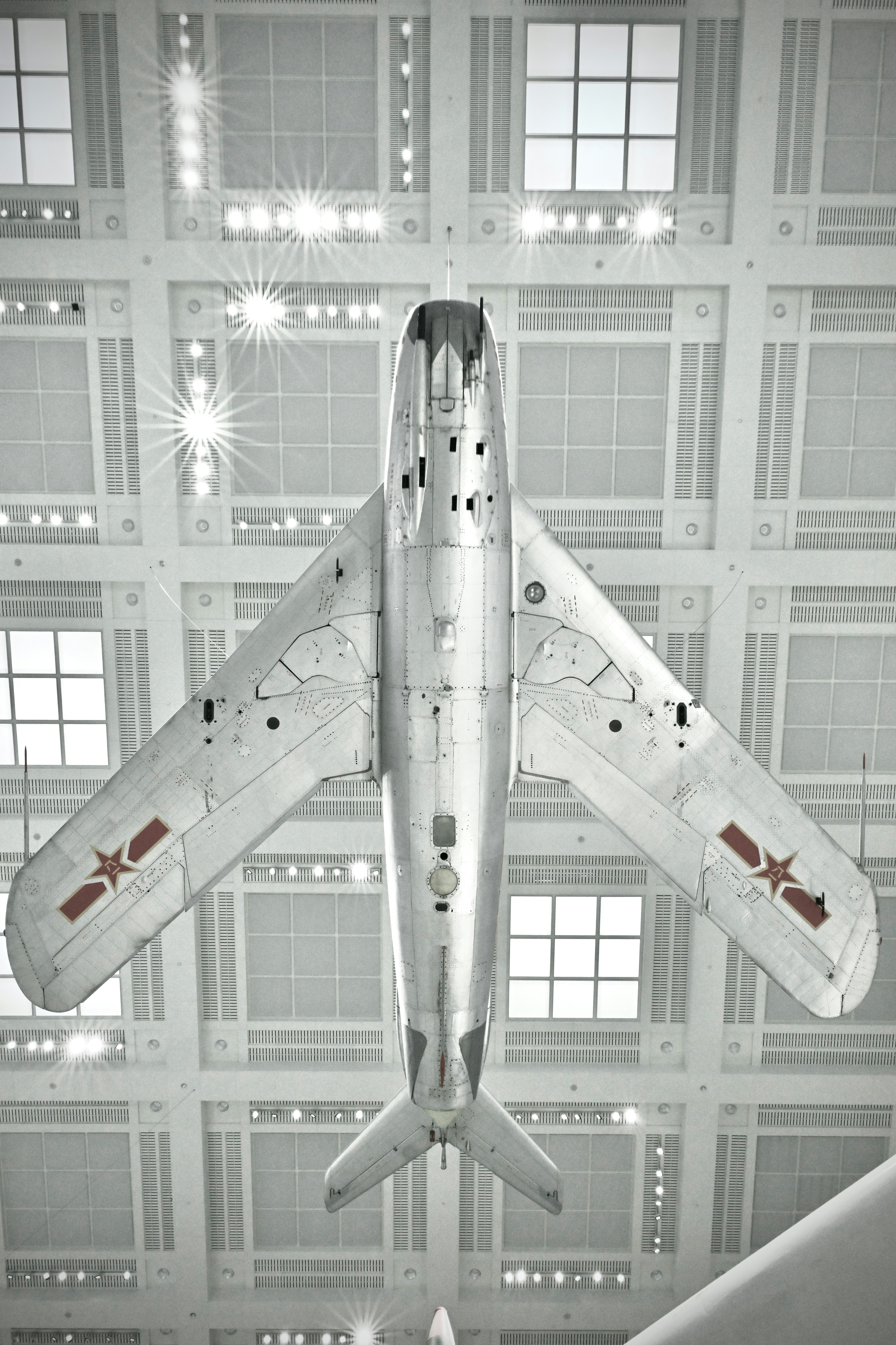 Midair Relic: A Silver Jet Suspended Beneath a Geometric Ceiling