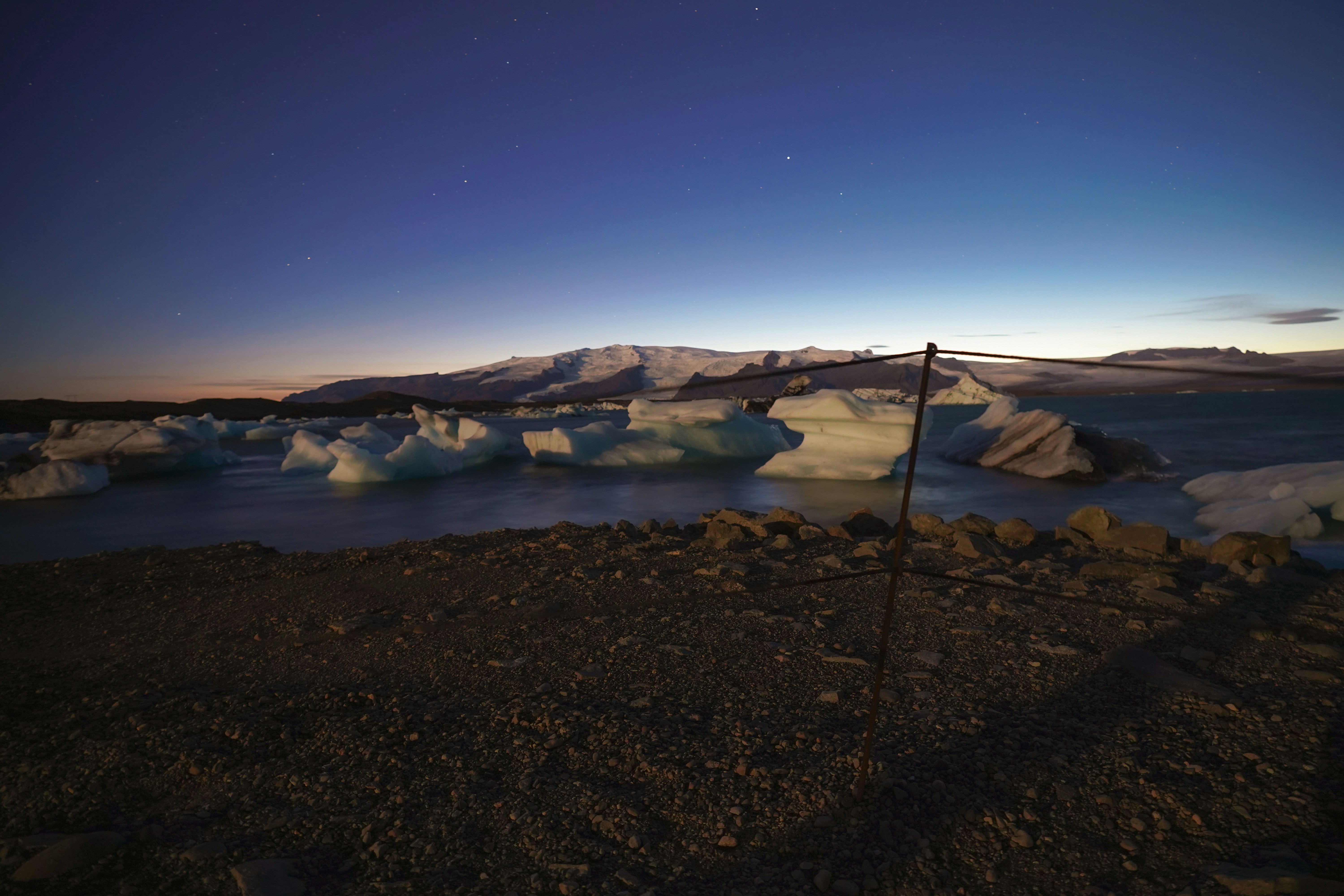 Dawn over Ice-Strewn Shore: Quiet Horizon and Silhouetted Rig