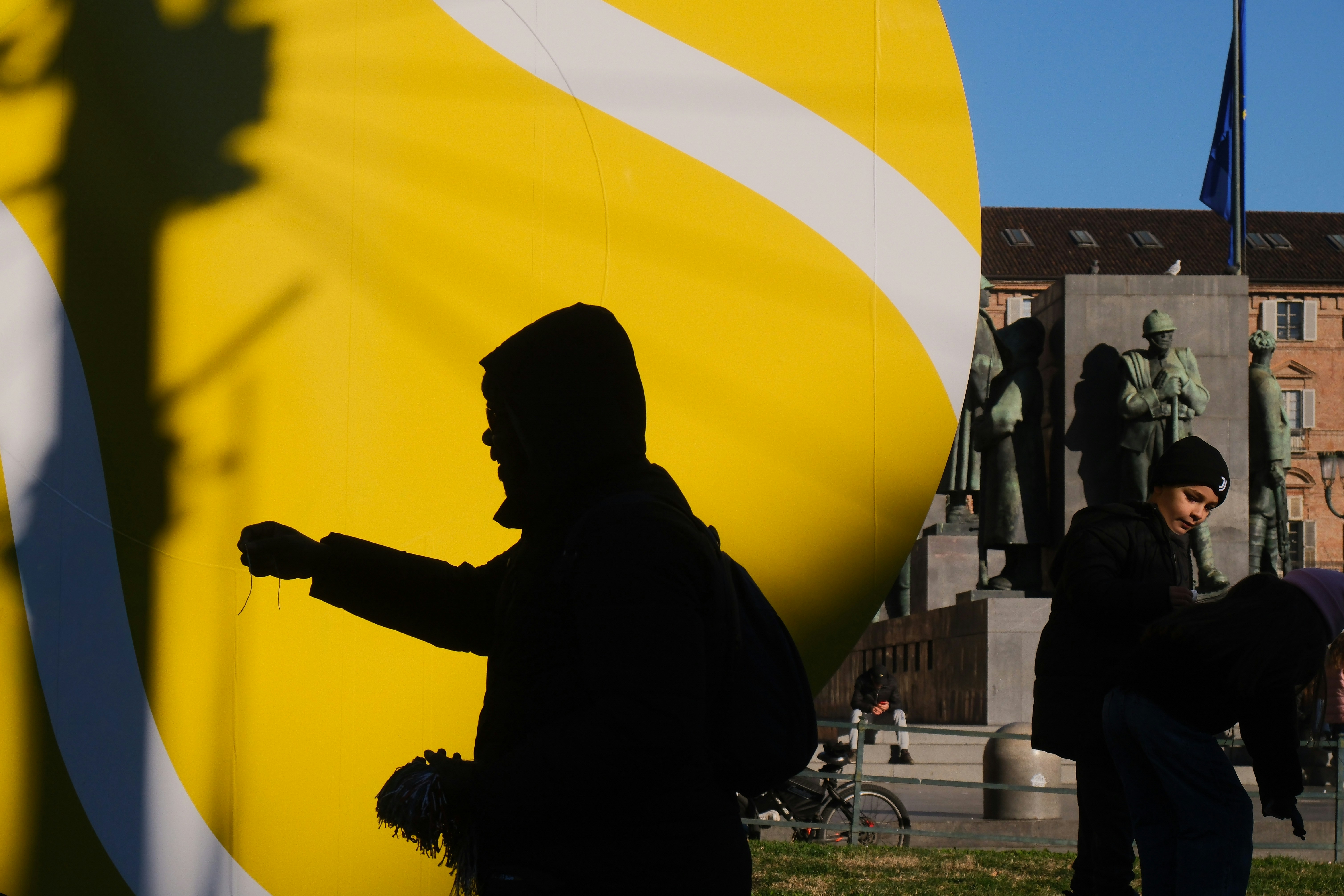 Silhouette at the Giant Yellow Shape in a Busy Plaza