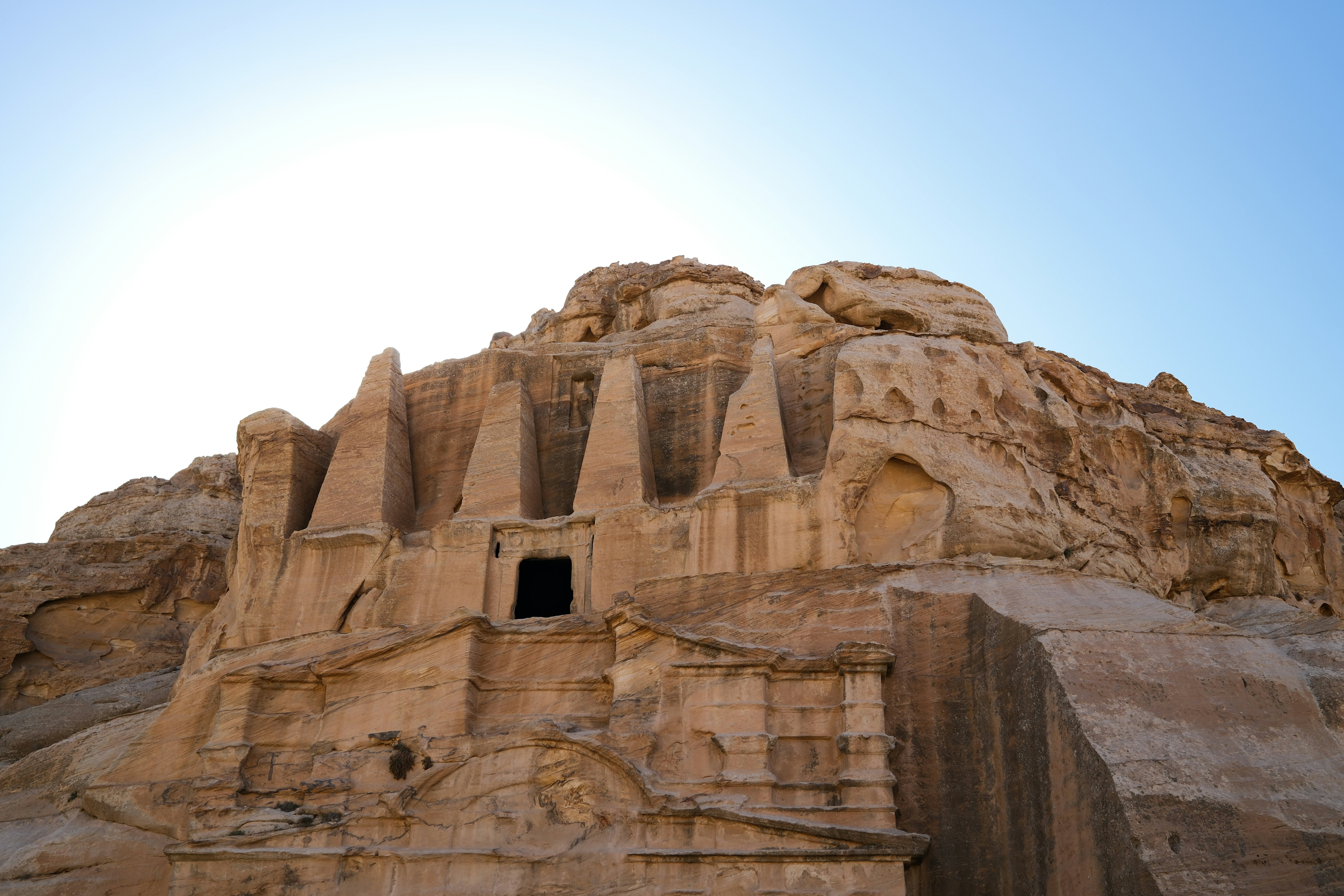 Ancient Silent Facade: Carved Cliff Monuments under a Wide Blue Sky