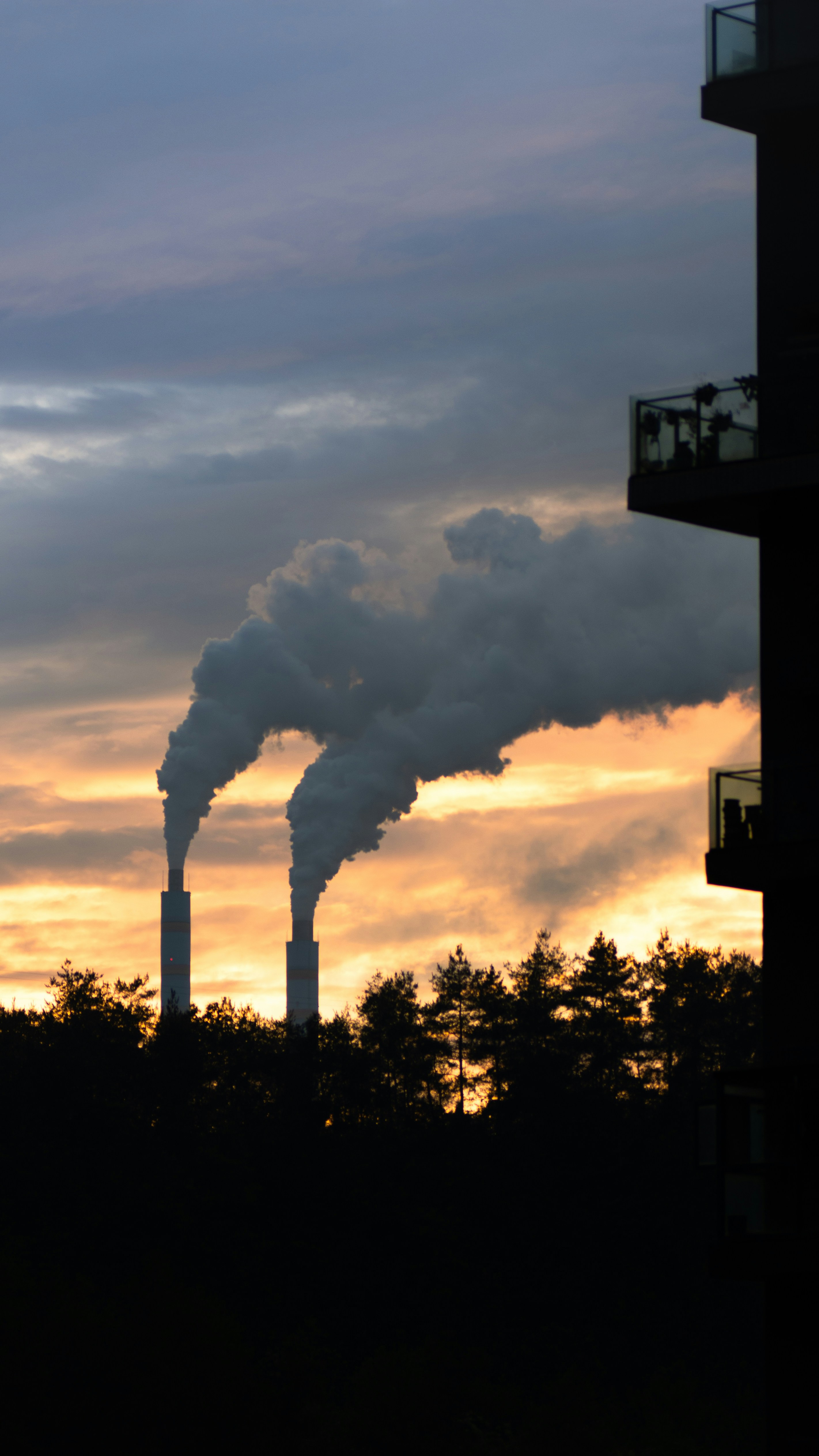 Industrial dusk: smokestacks silhouette against sunset clouds