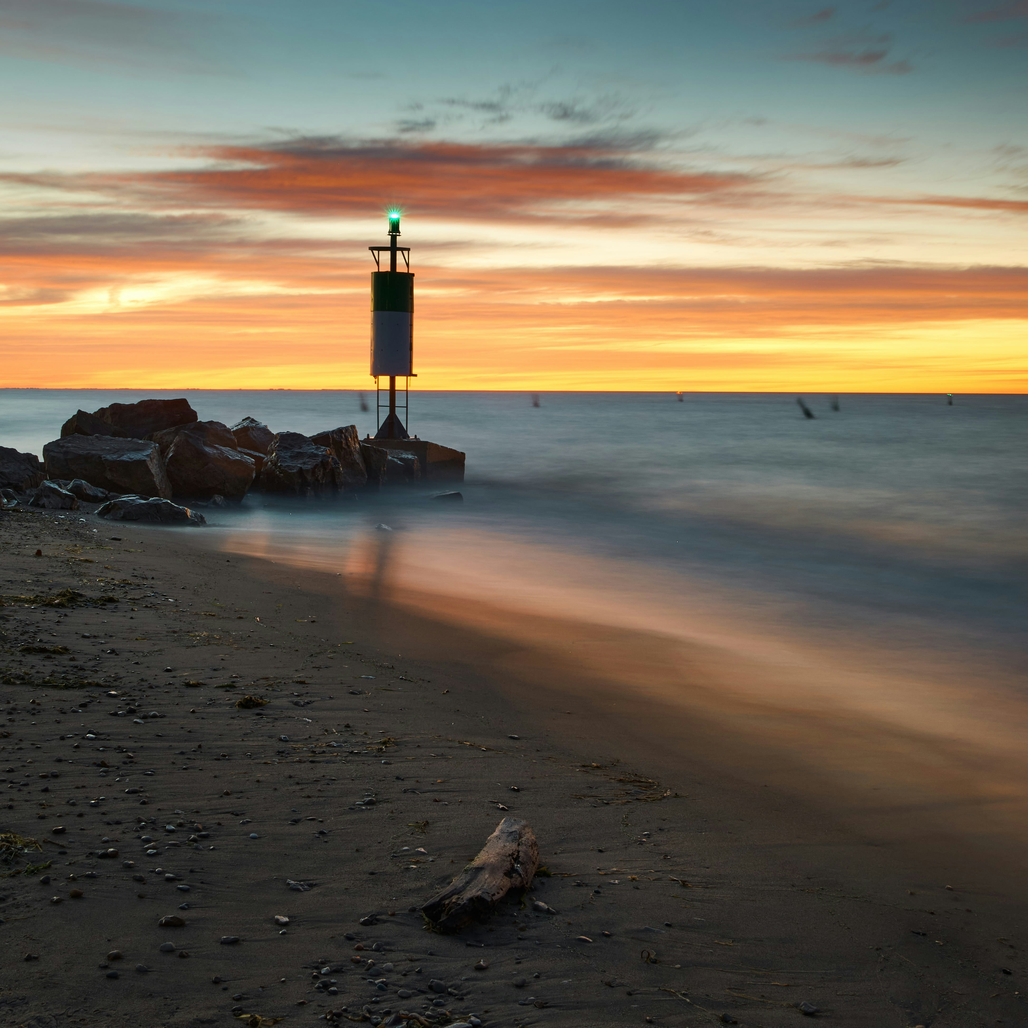Distant Green Light Over a Quiet Sea: A Sunset Beacon