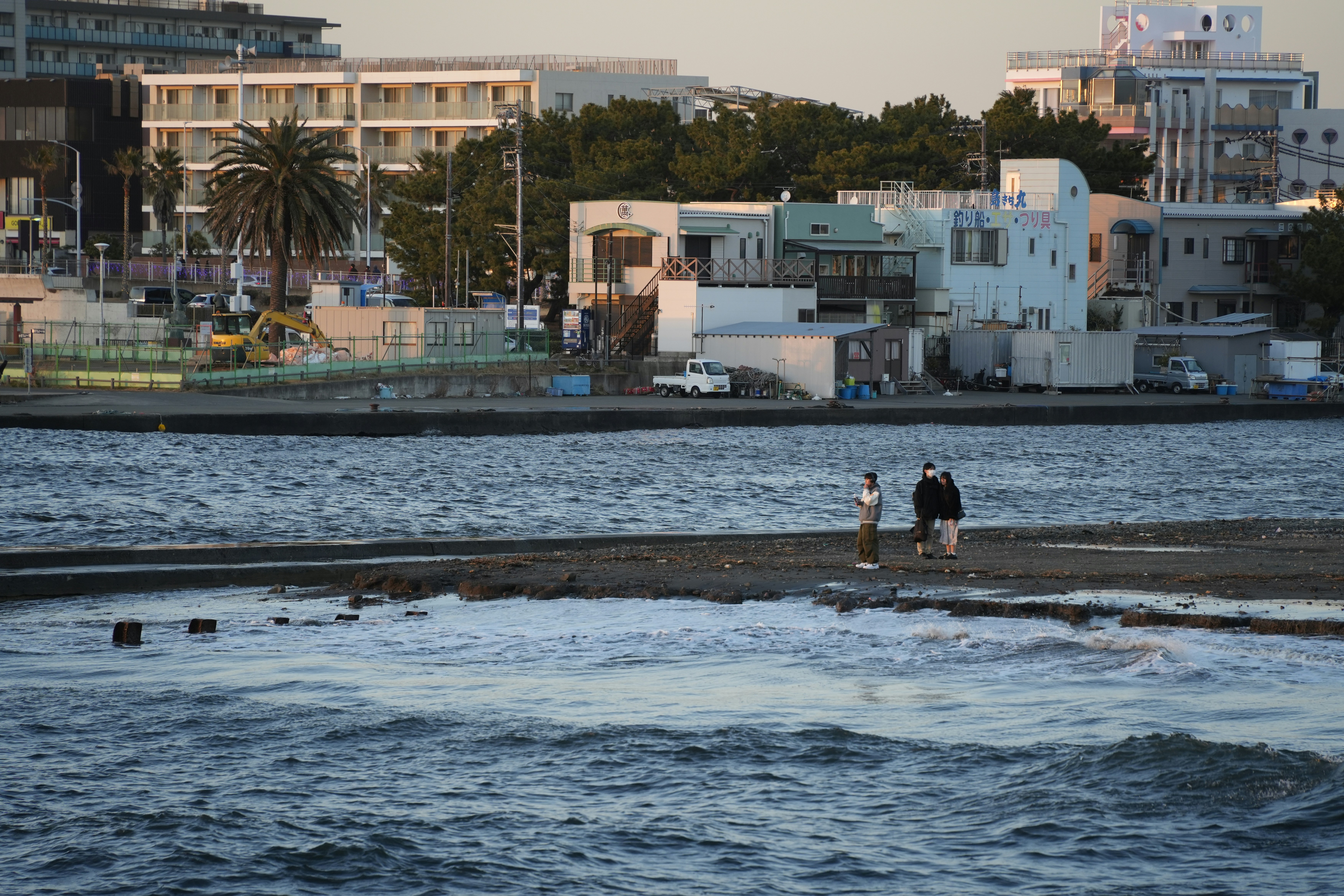 Evening by the Pier: Two Figures Walk the Narrow Strip of Shore