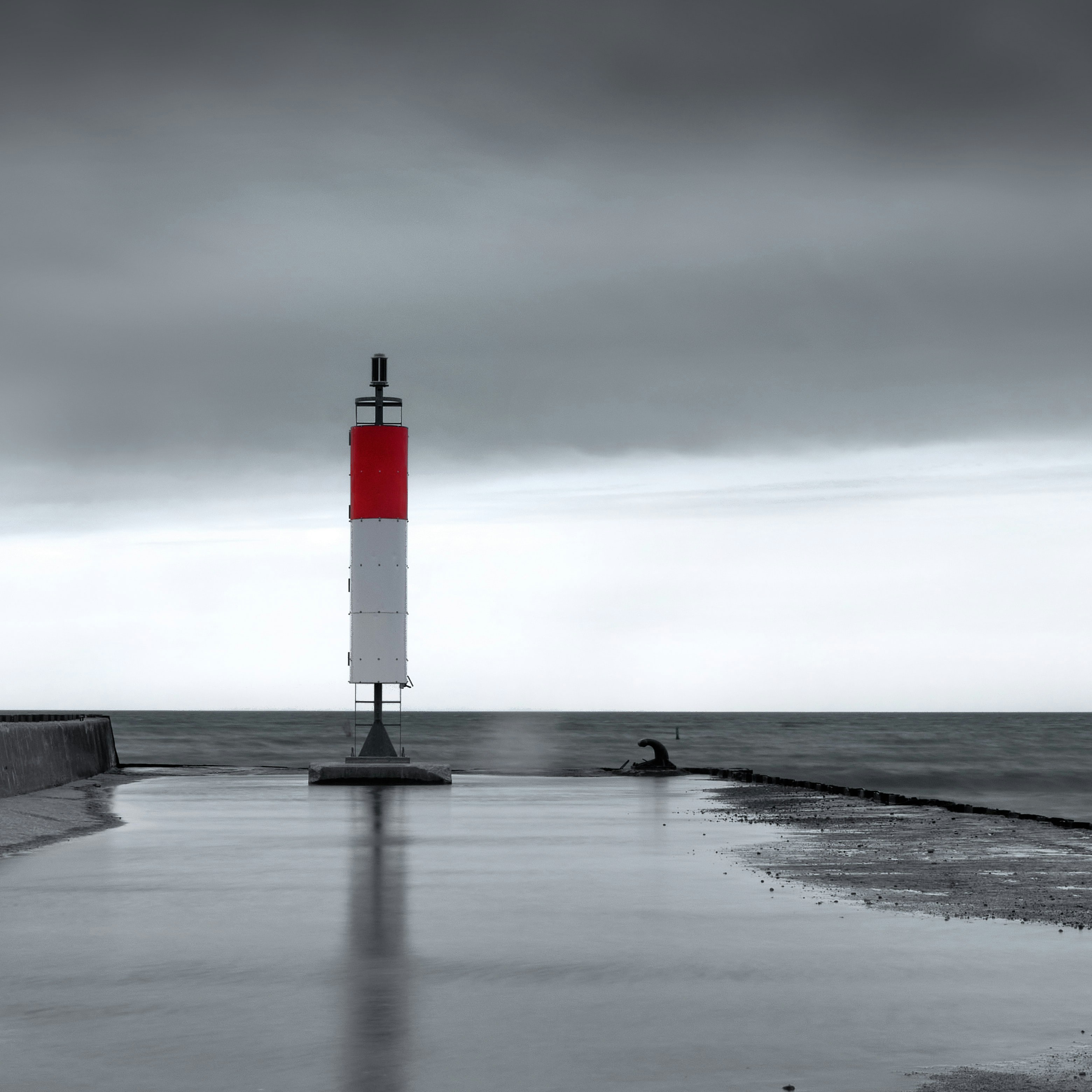 Red and White Beacon at the Edge of a Calm Horizon