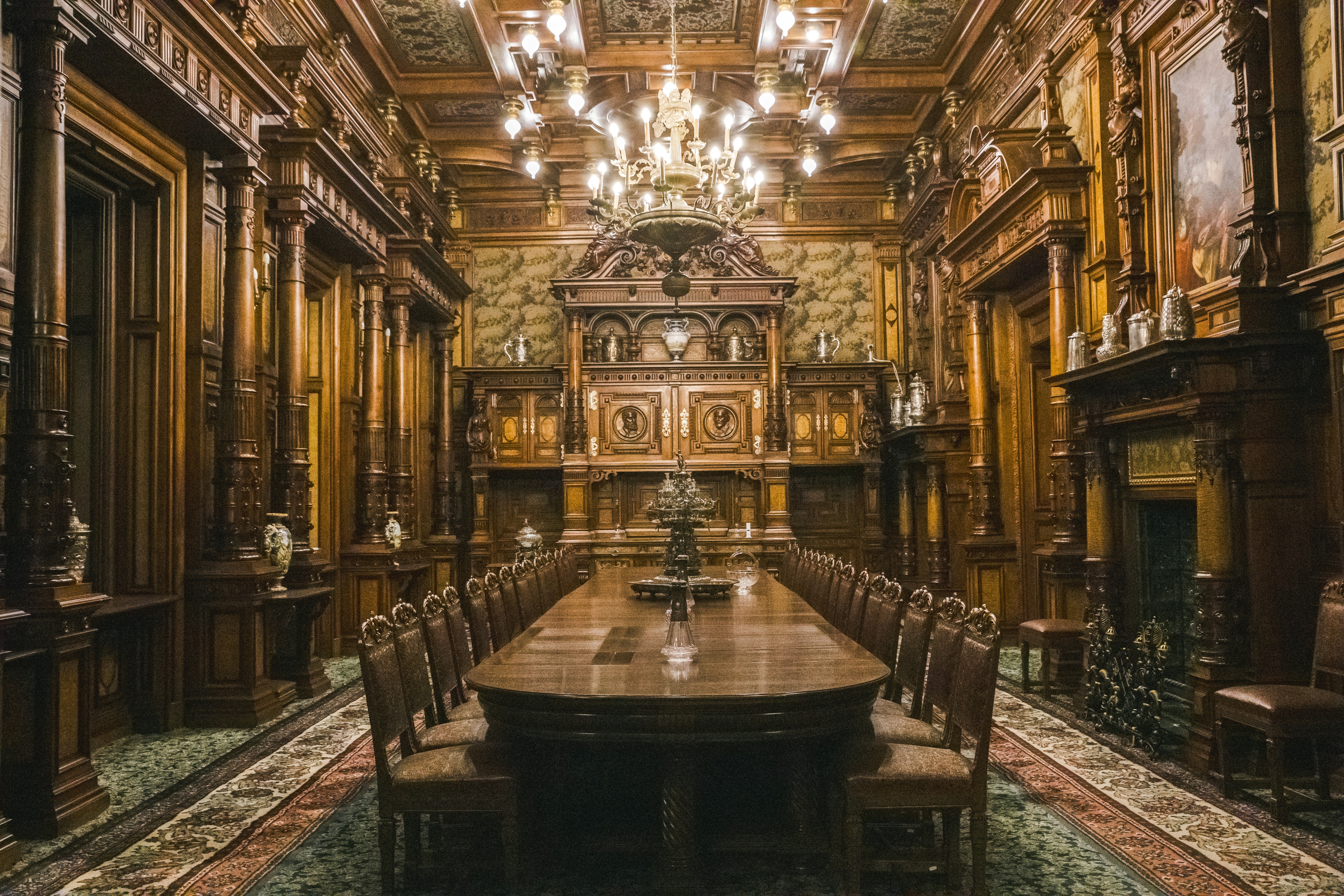 Ornate Heritage Hall: A Long Table Enveloped in Carved Wood and Warm Light