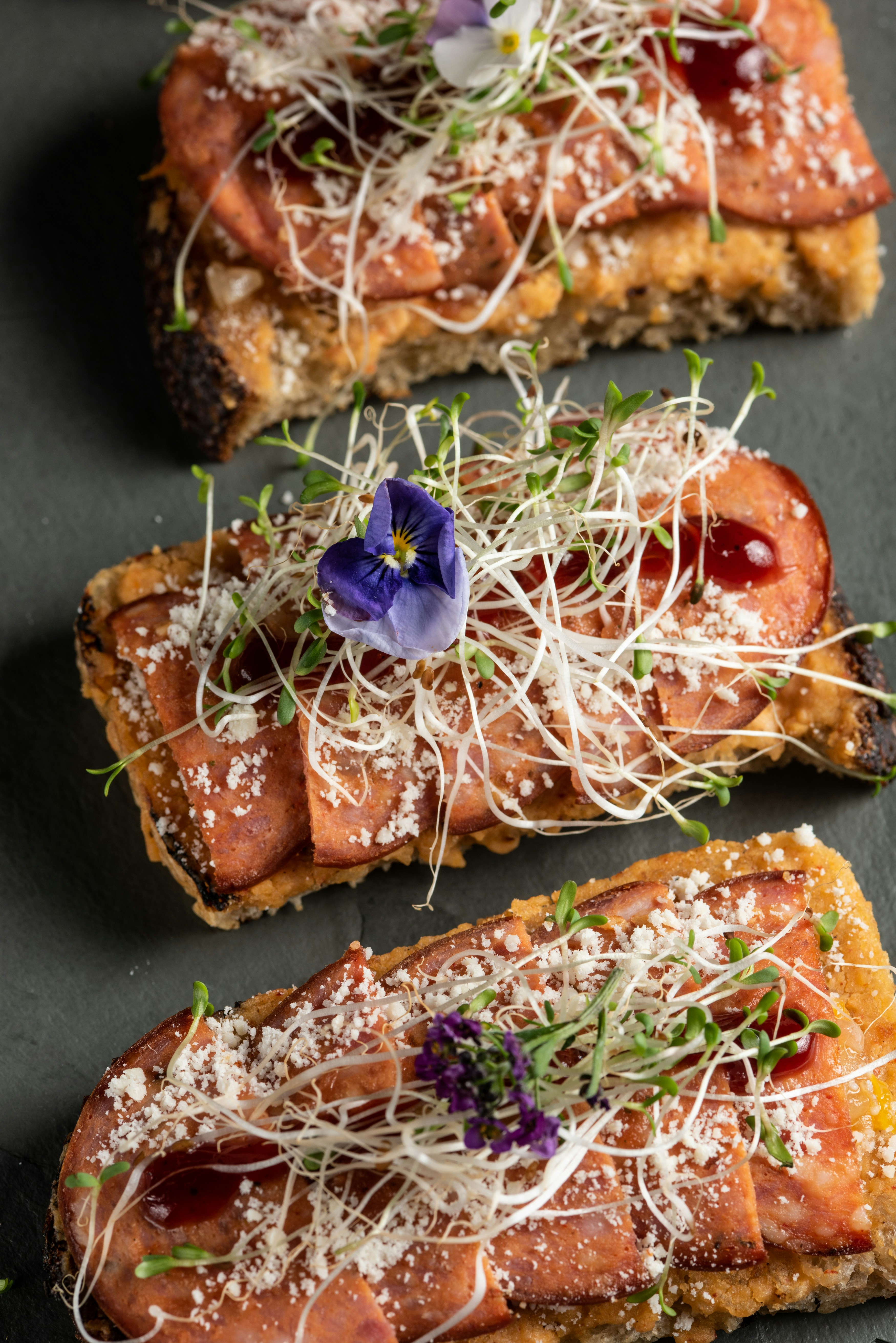 Flaked salmon toasts crowned with microgreens and edible blossoms