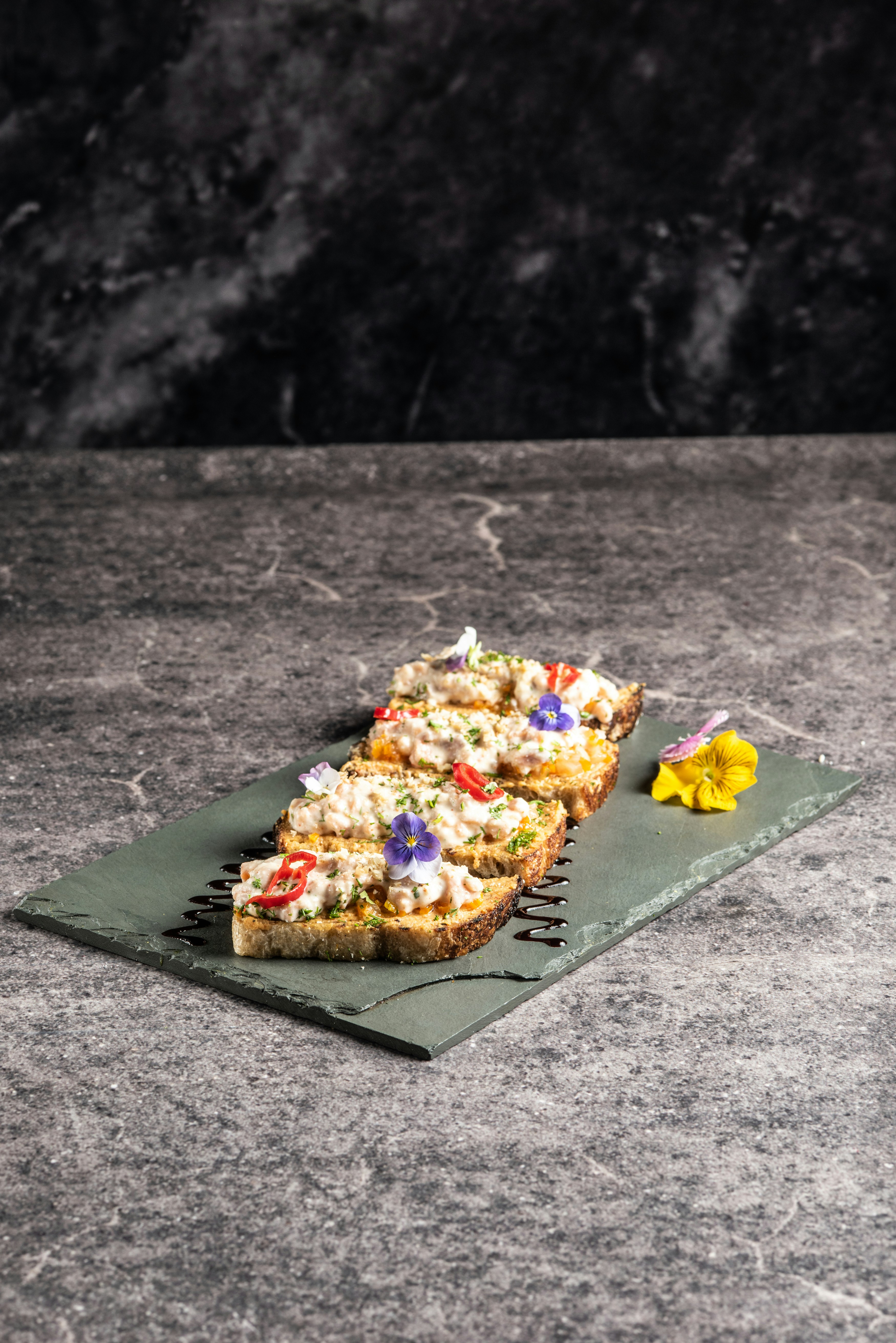 Edible Floral Toasts: a trio of herbaceous bites on a slate.