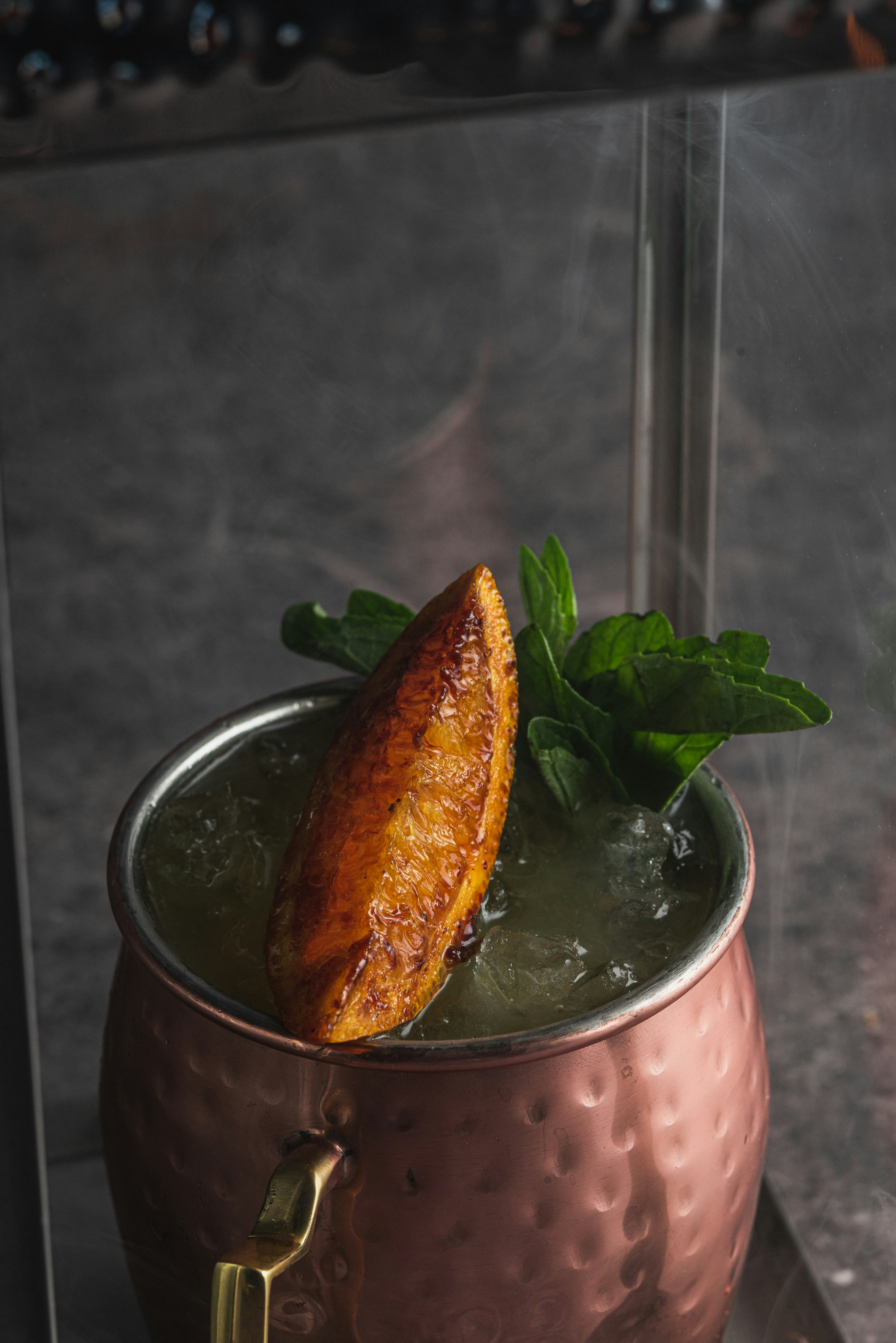 Citrus-glazed garnish resting in a copper mug of iced herbal cocktail