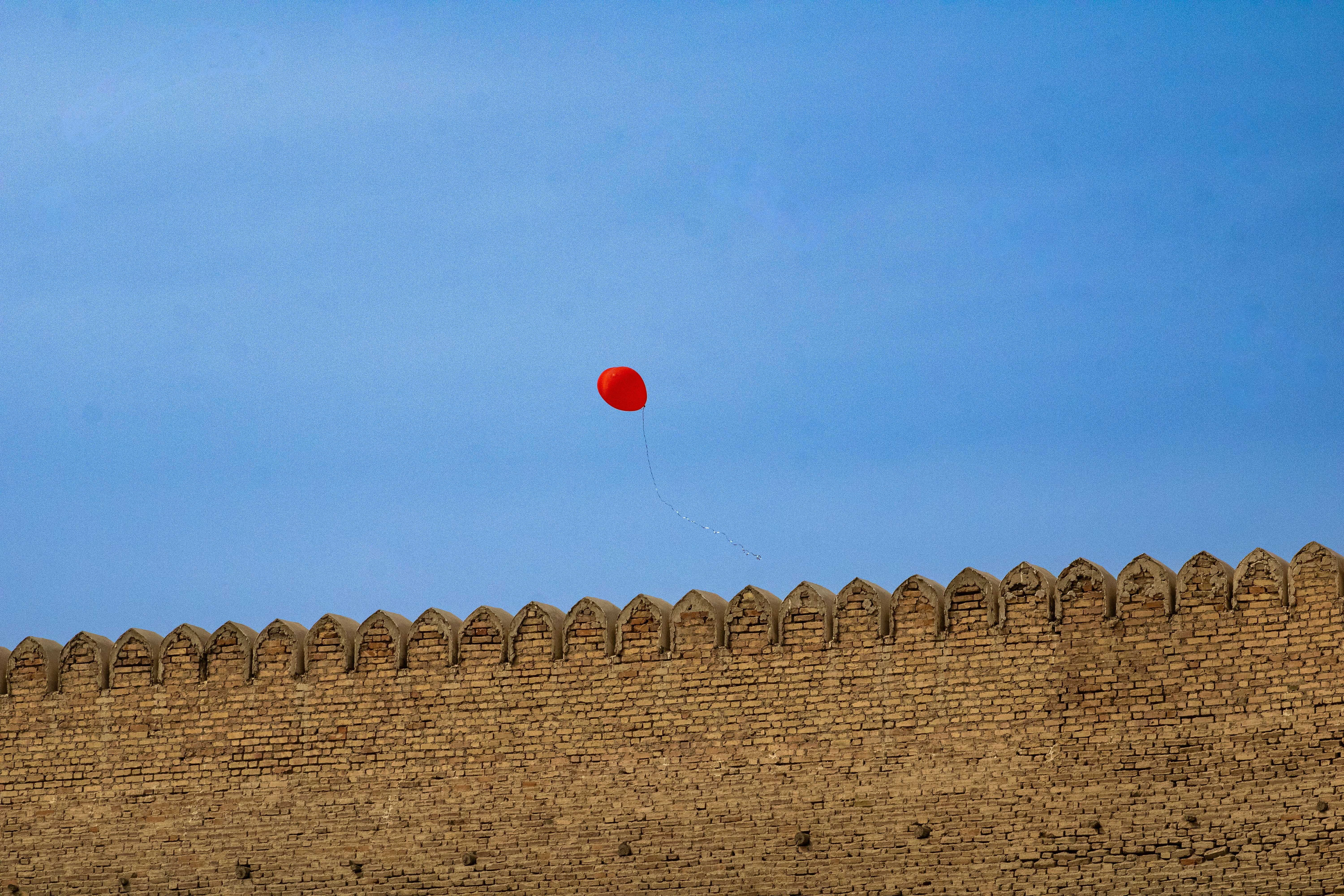 Red Balloon Above the Terracotta Wall