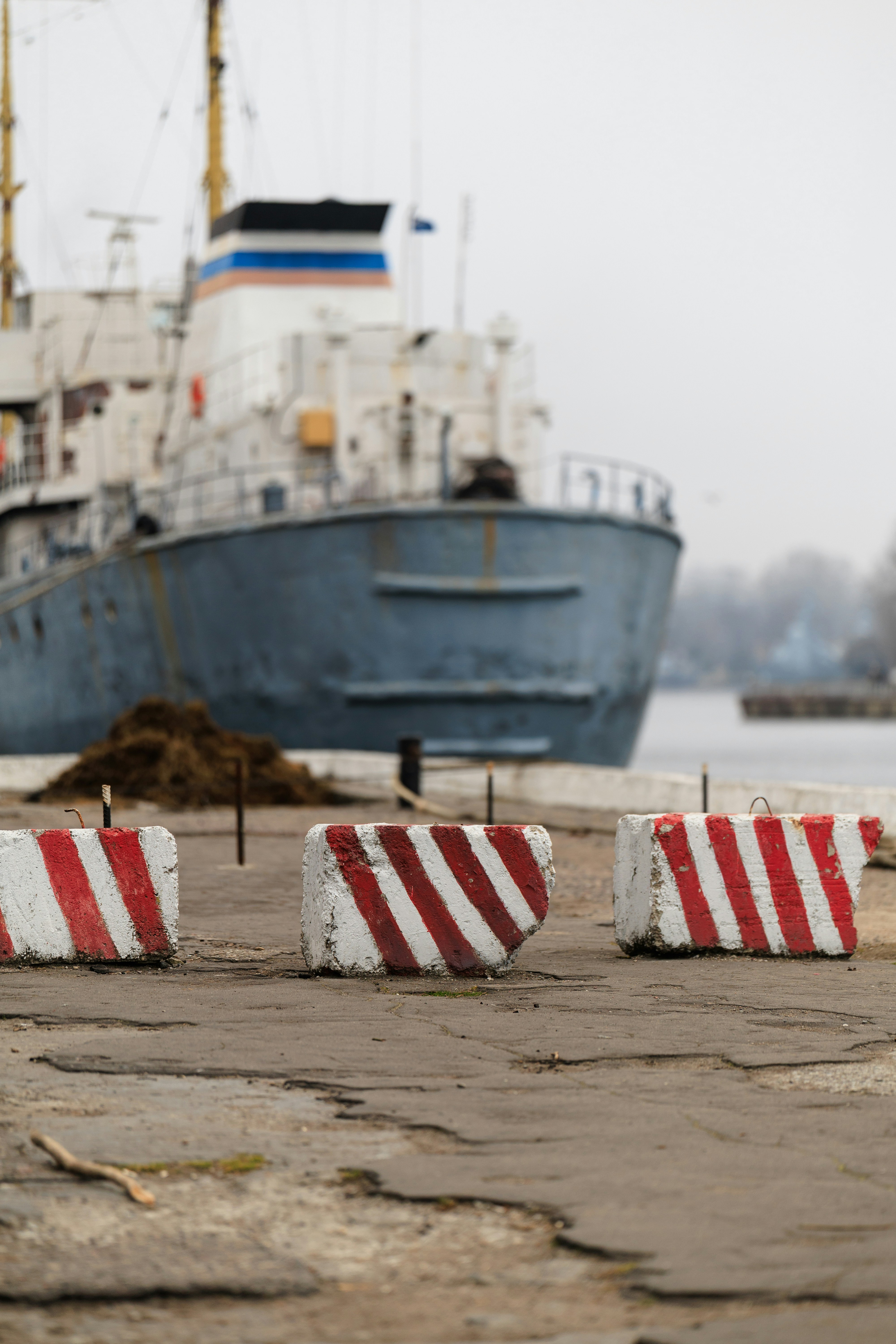 Dockside Red-and-White Barriers with a Distant Blue Vessel