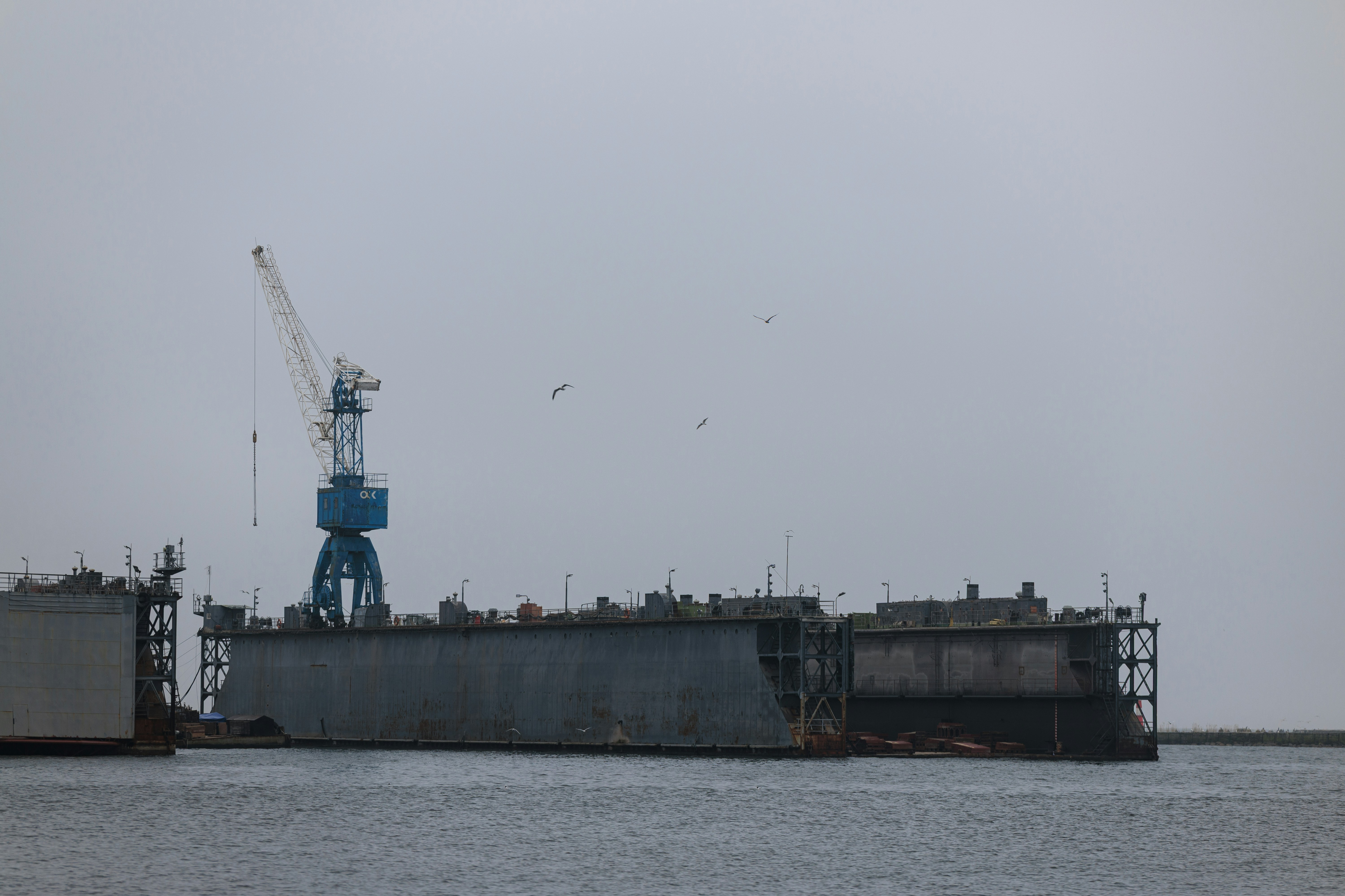 Industrial Pier: Crane, Gate, and Water in Quiet Horizon
