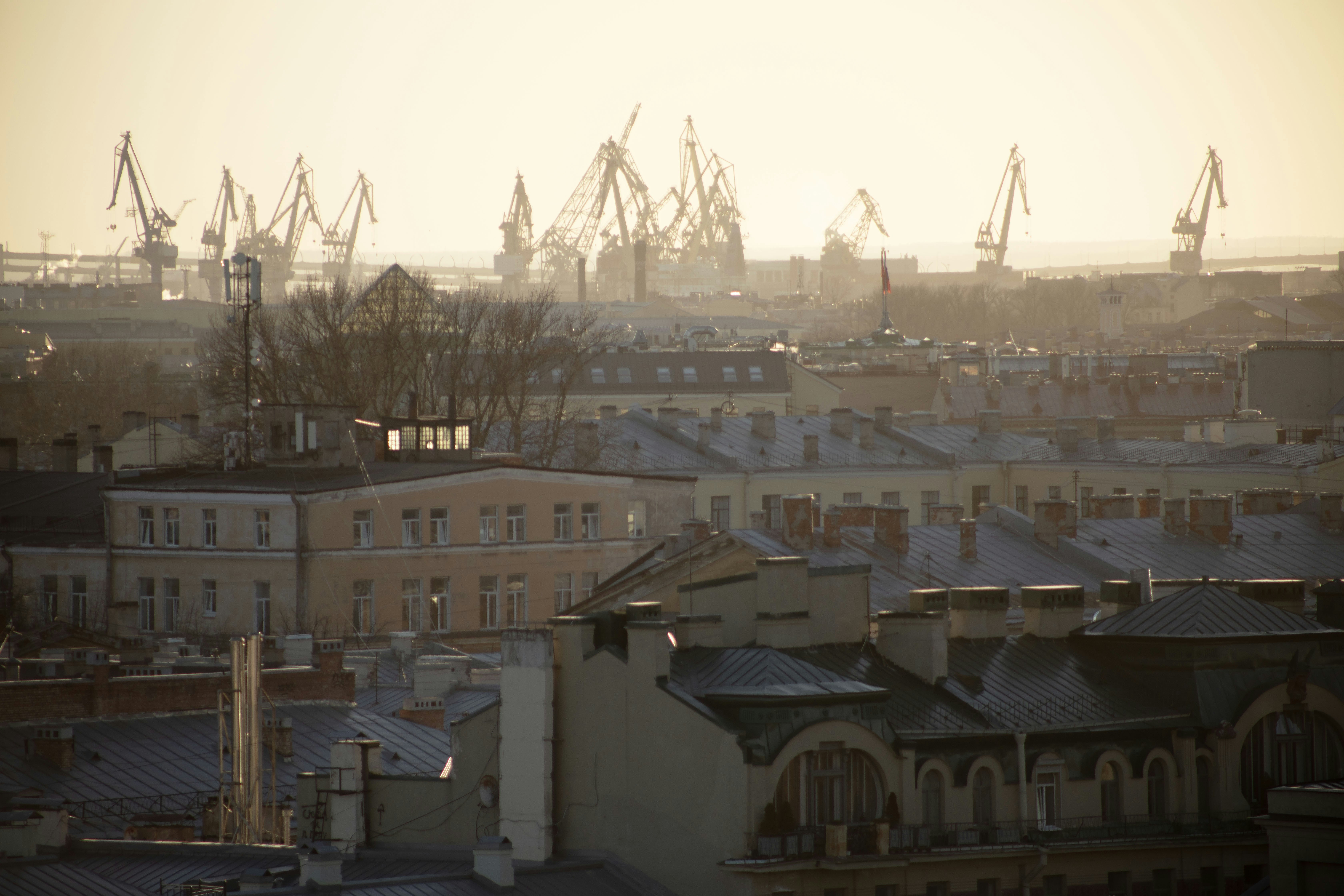 Sunlit Harborscape: Distant Cranes Above the Quiet Rooftops