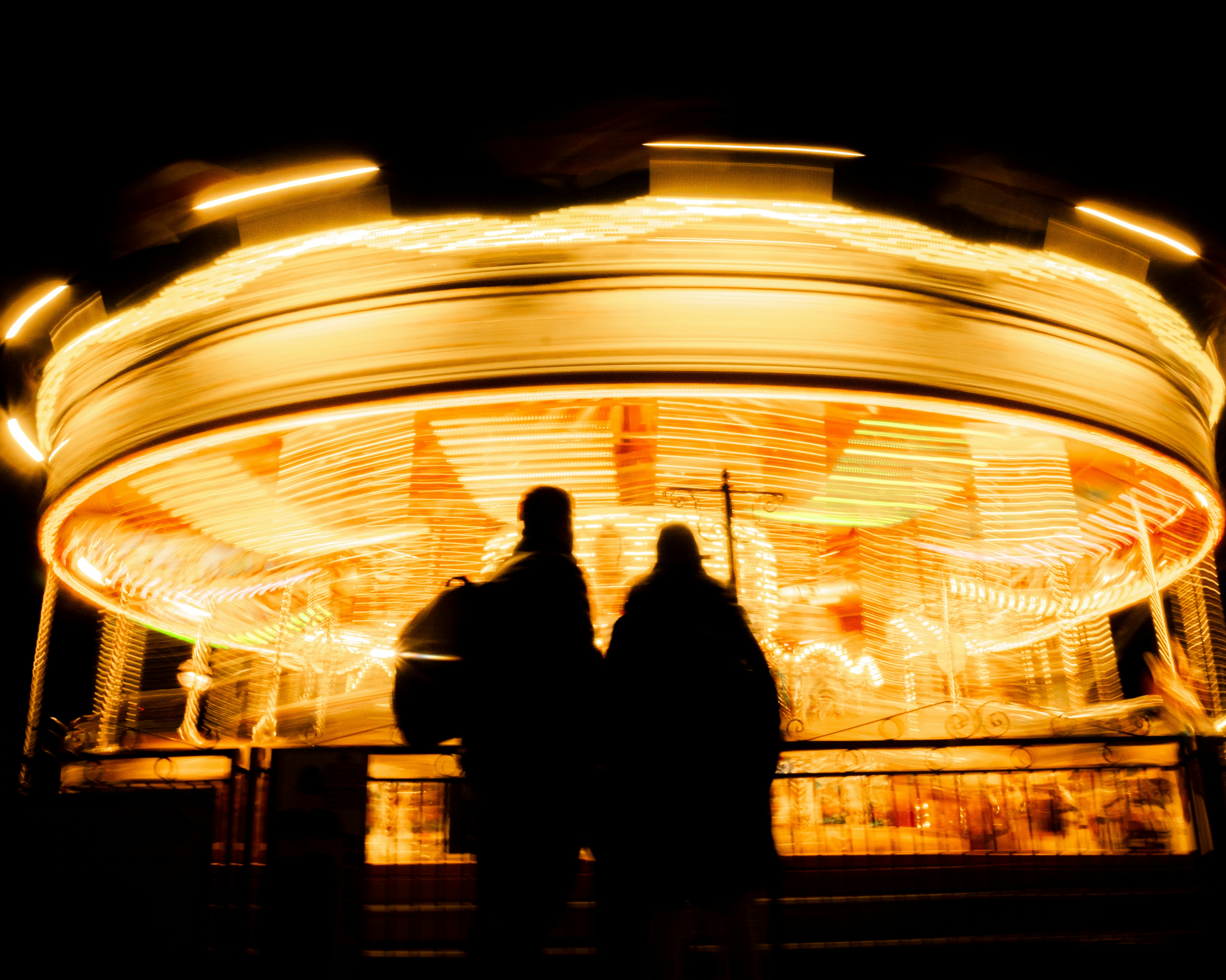 Silhouetted Riders in a Spin: Night Carousel Blur