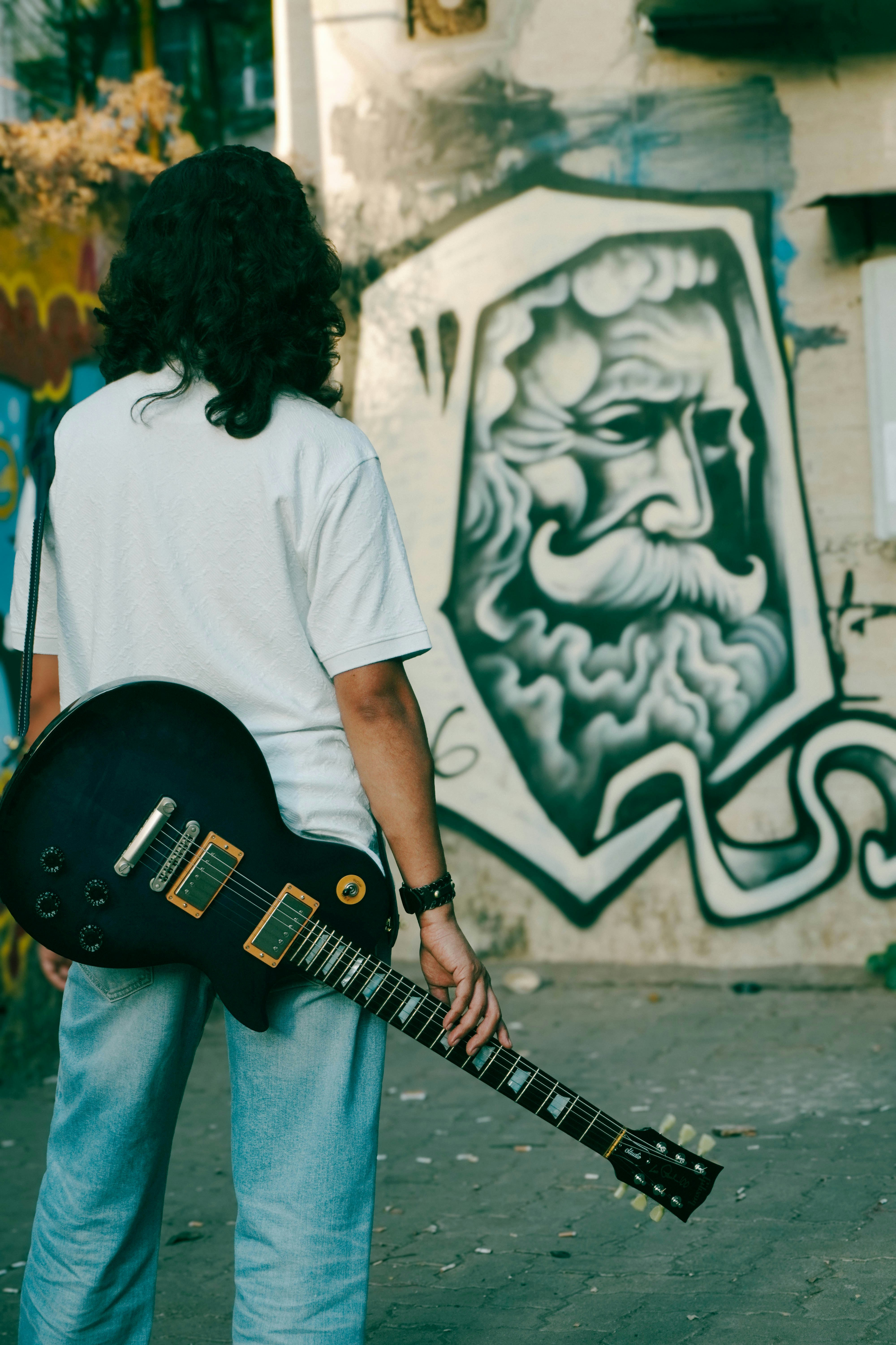 Guitarist in Urban Graffiti: Portrait by the muraled bearded face