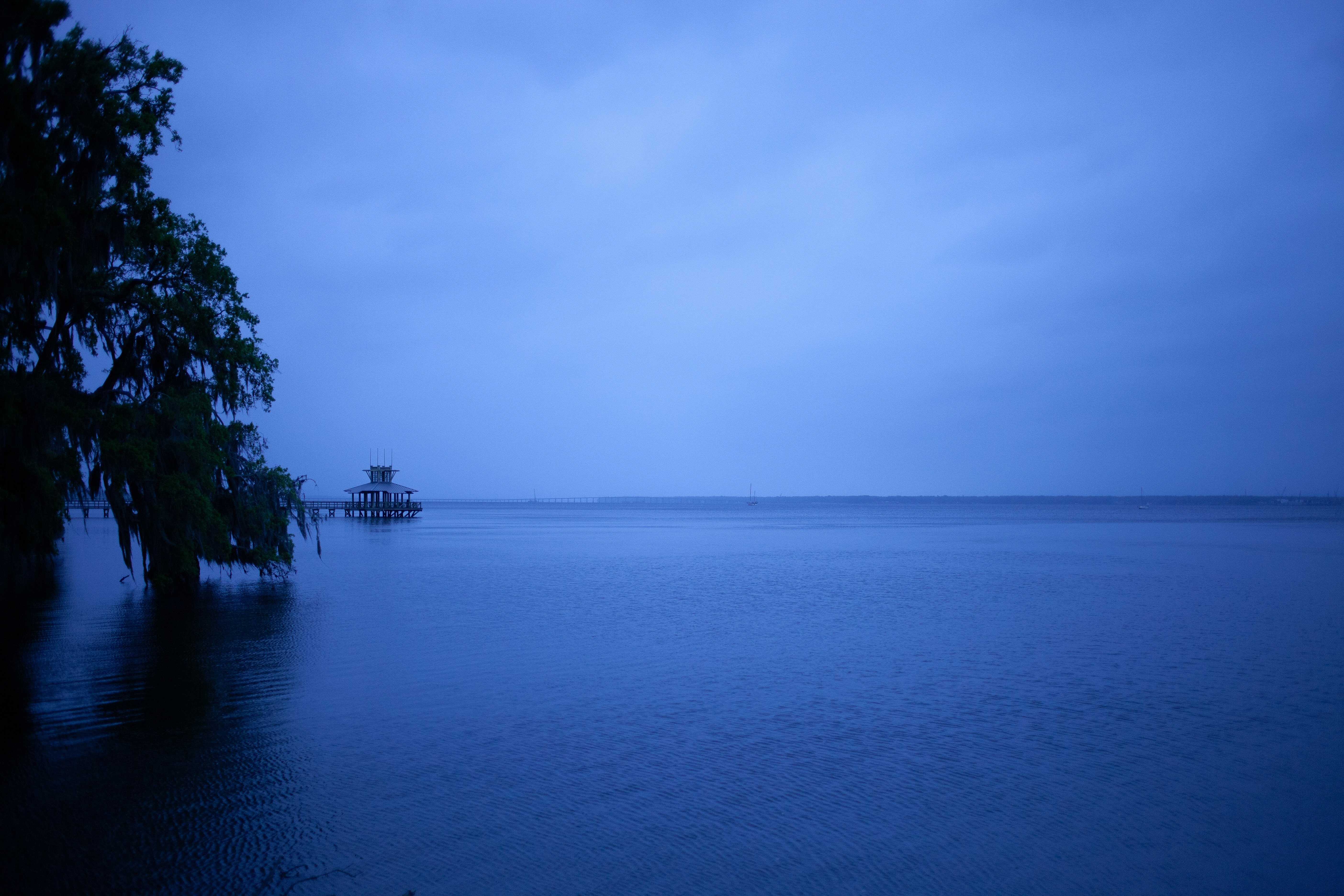 Blue Hour Over the Quiet Sea: A Distant Pier Stretches Toward the Horizon.