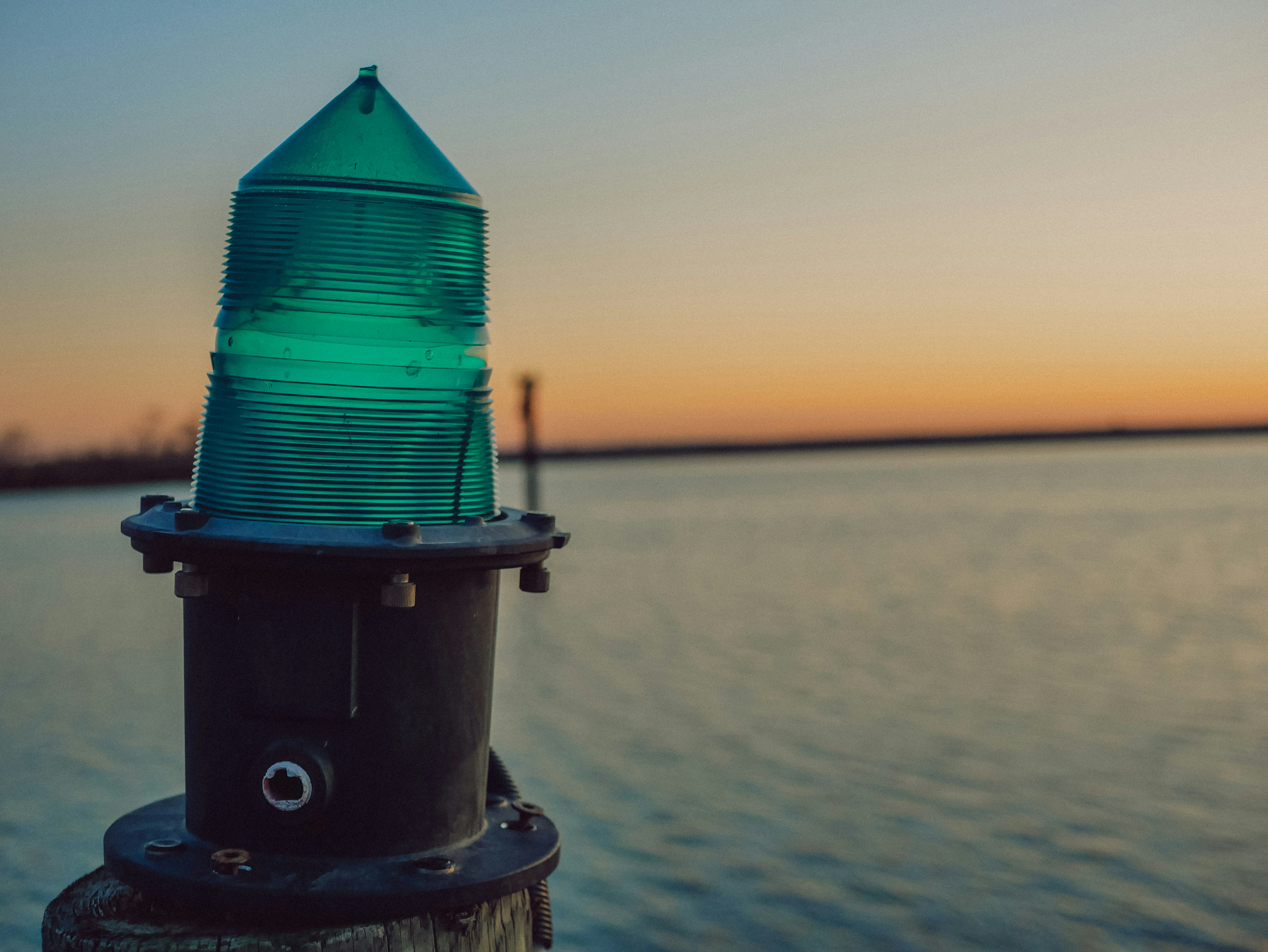 Green beacon at dusk over calm water