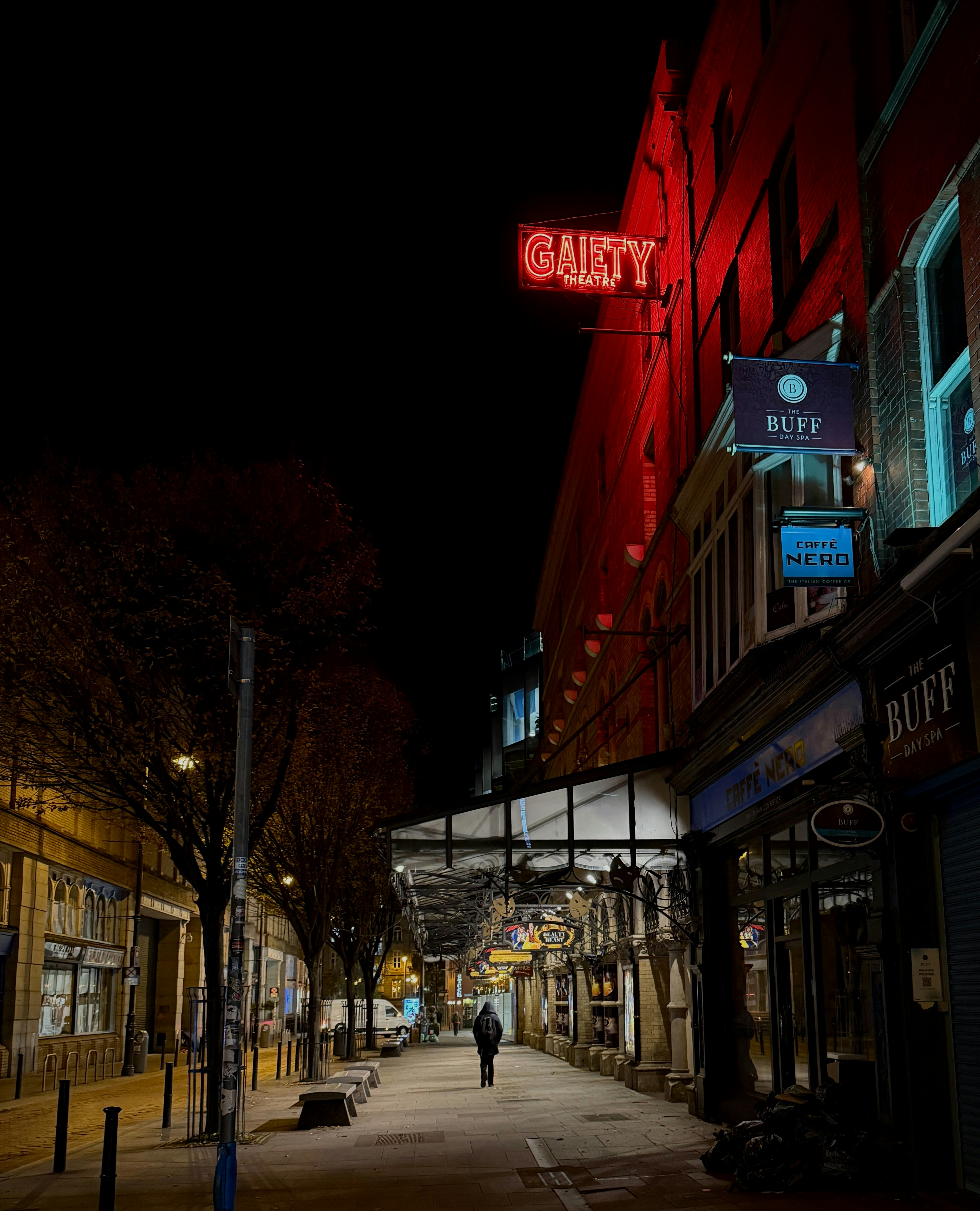 A lone figure walks down a dark alley at night.