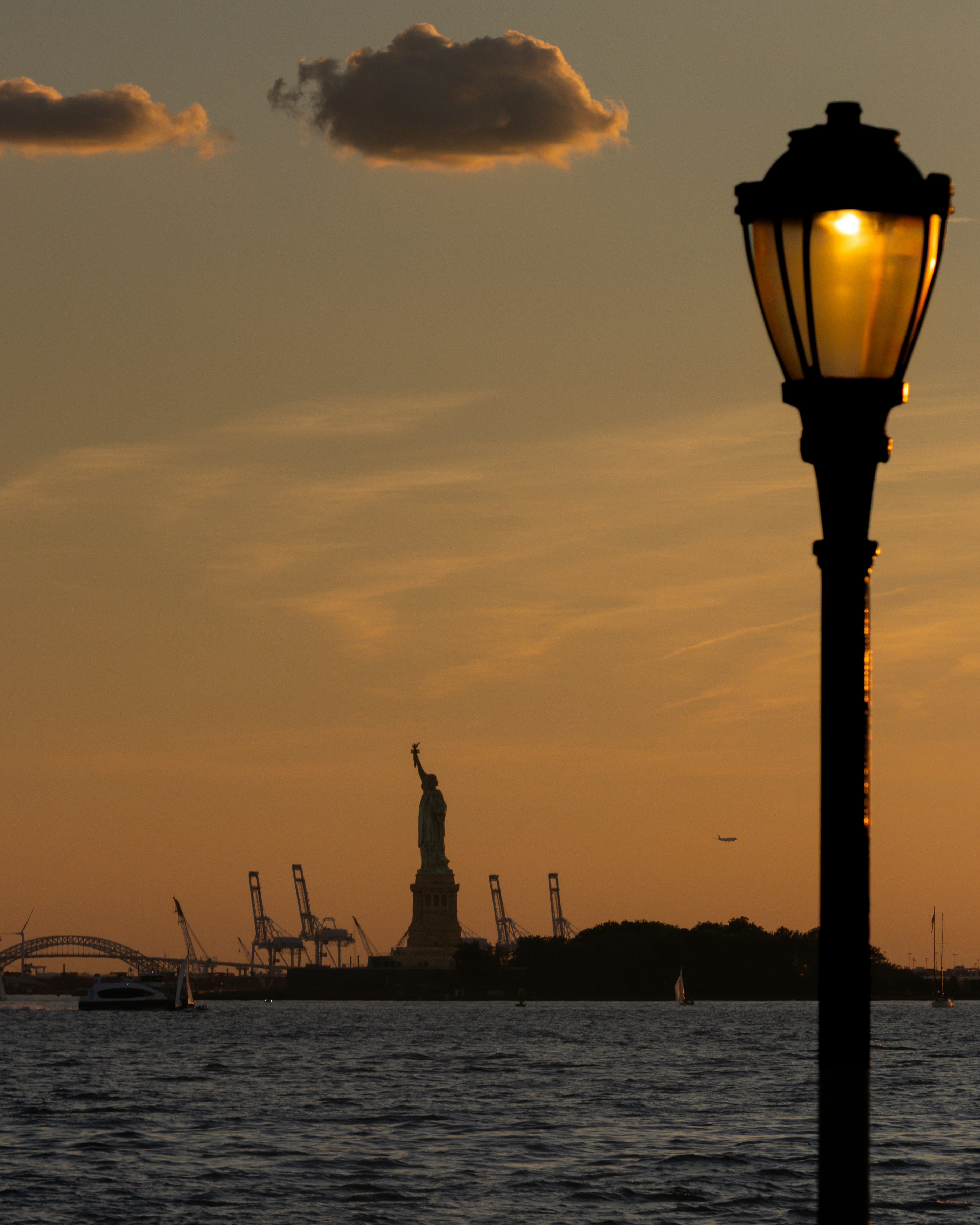 Golden Hour by the Waterfront: Statue of Liberty Silhouette at Dusk