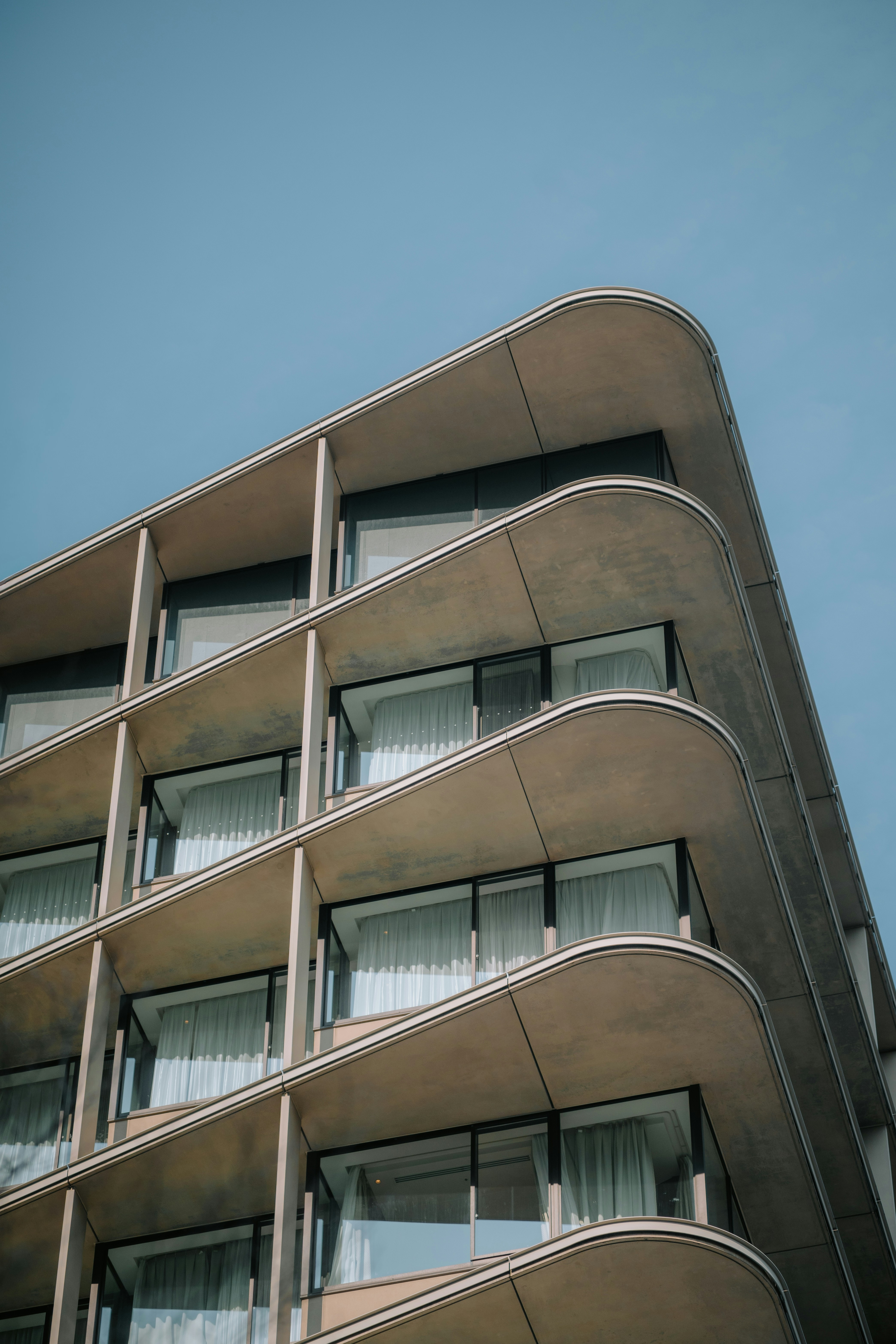 Diagonal Facade: Curved Balconies in a Pale-Blue Sky