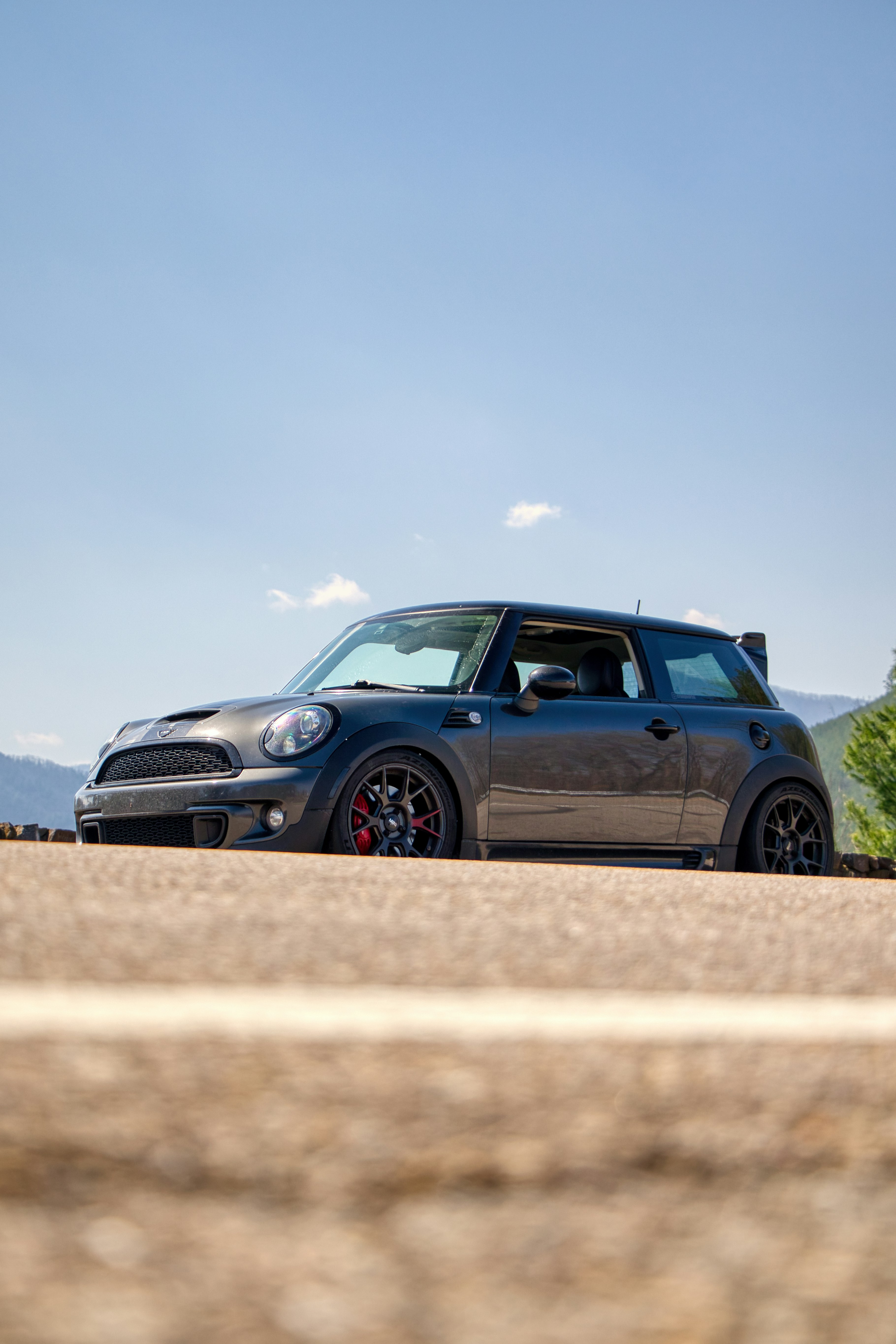Grey Mini Cooper S tucked into a sunlit hilltop pose