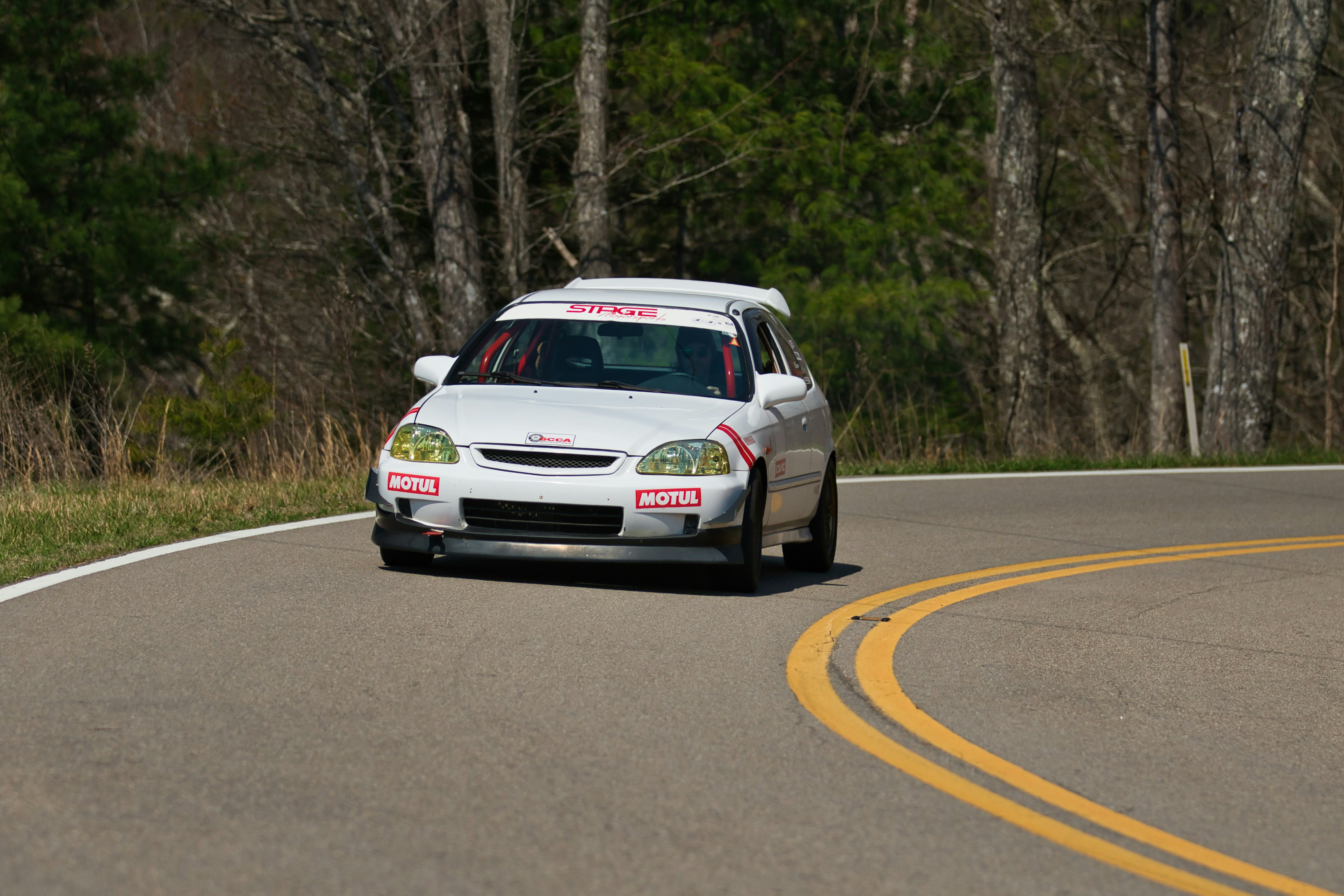 Curved Road Rally: White race car navigates a tight bend