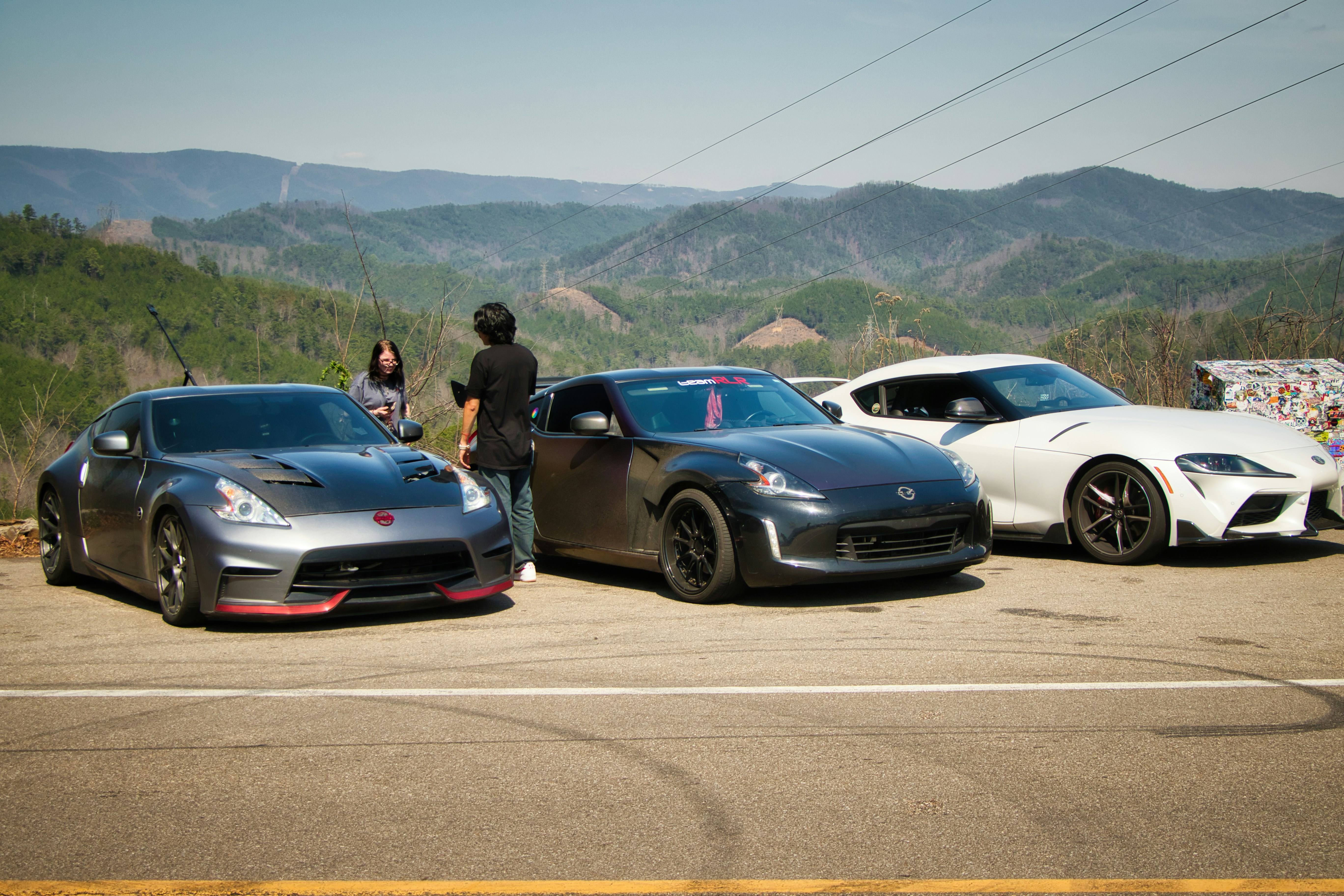Three Low, Aggressive Sports Cars Parked on a Scenic Ridge