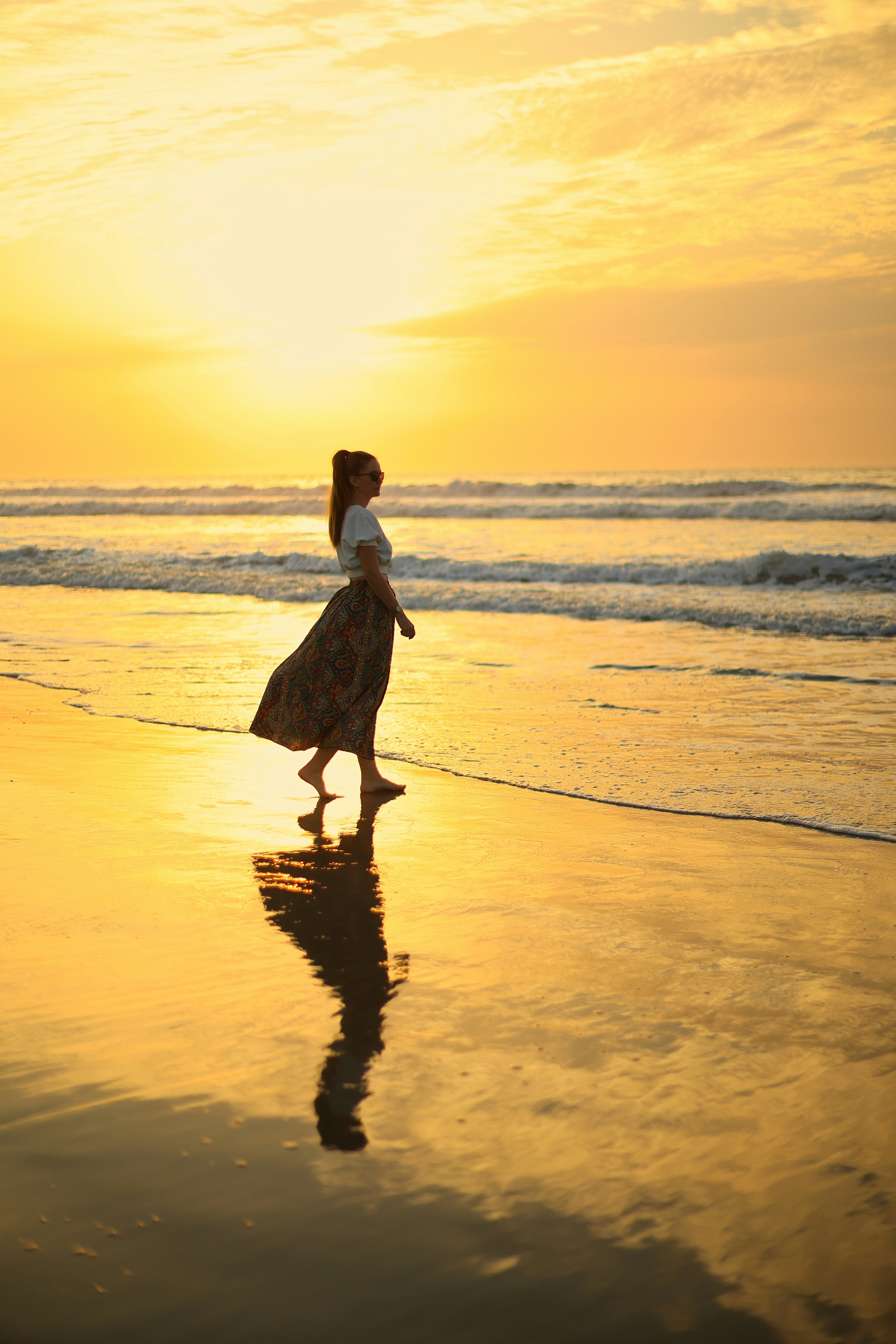 Silhouette in Golden Tide: A lone figure strolling the shoreline at sunset