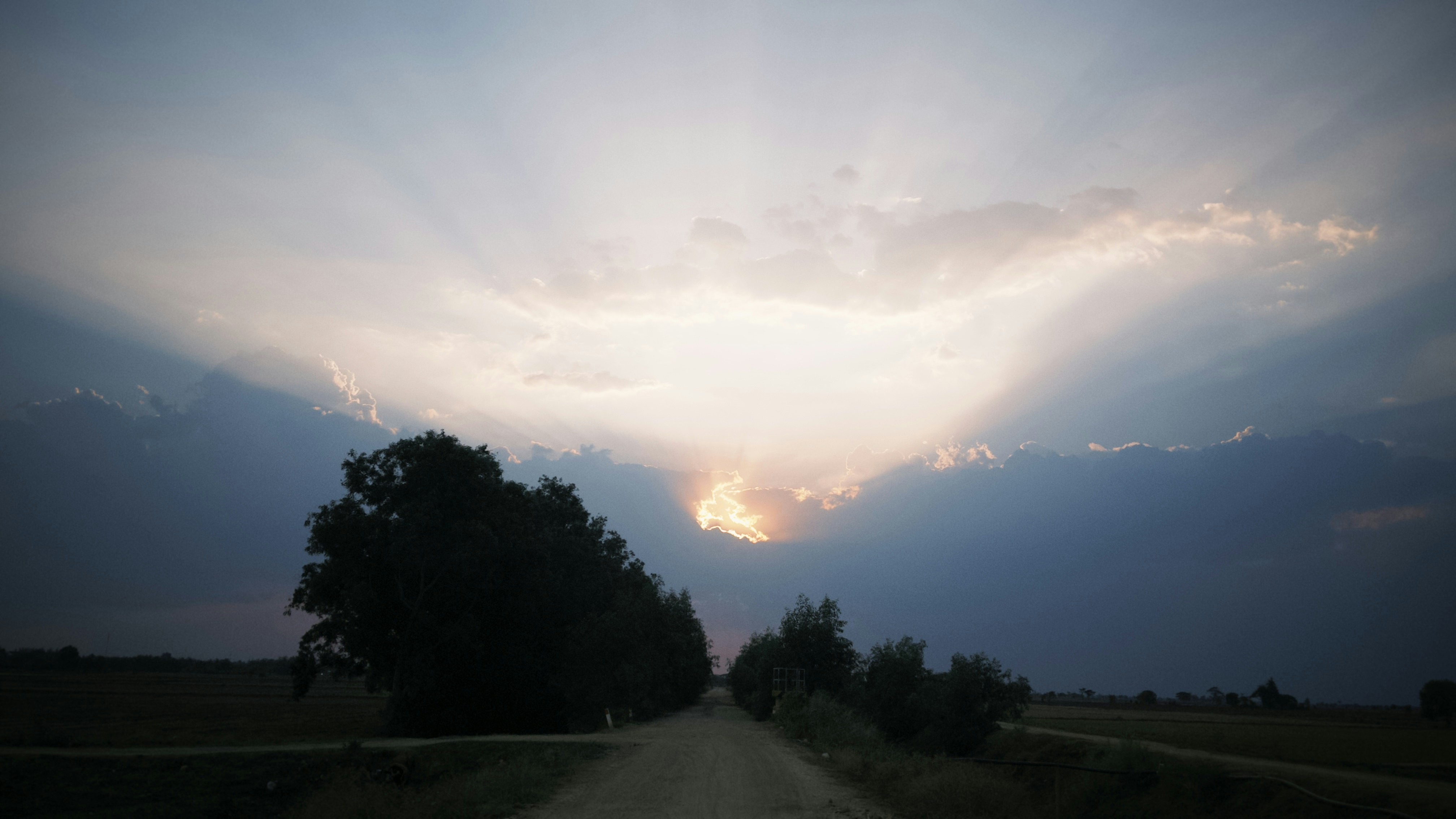 Dawn over a Rural Road: Light Breaks Through Clouds