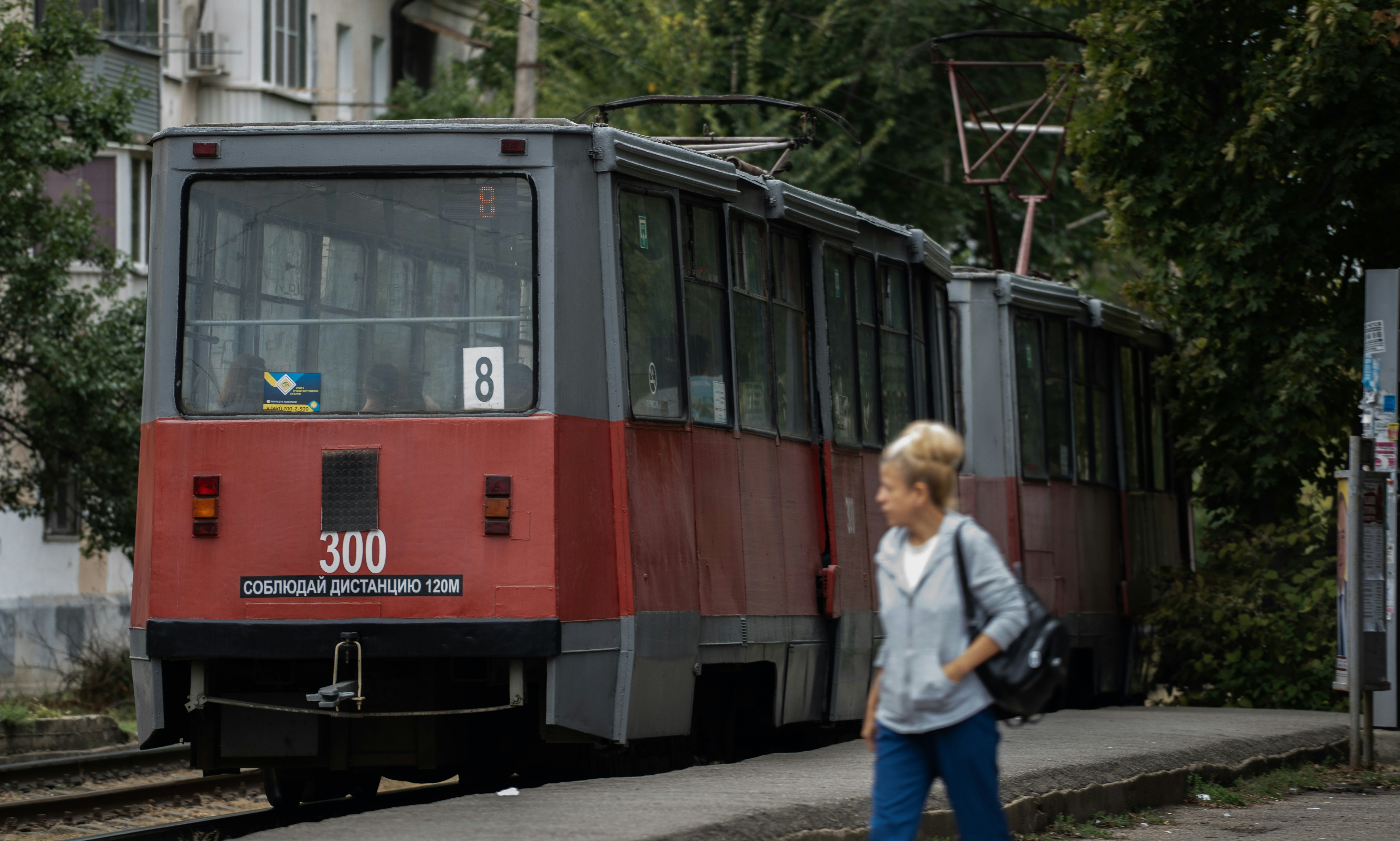 City Tram Passes by as a Pedestrian Crosses the Quiet Street
