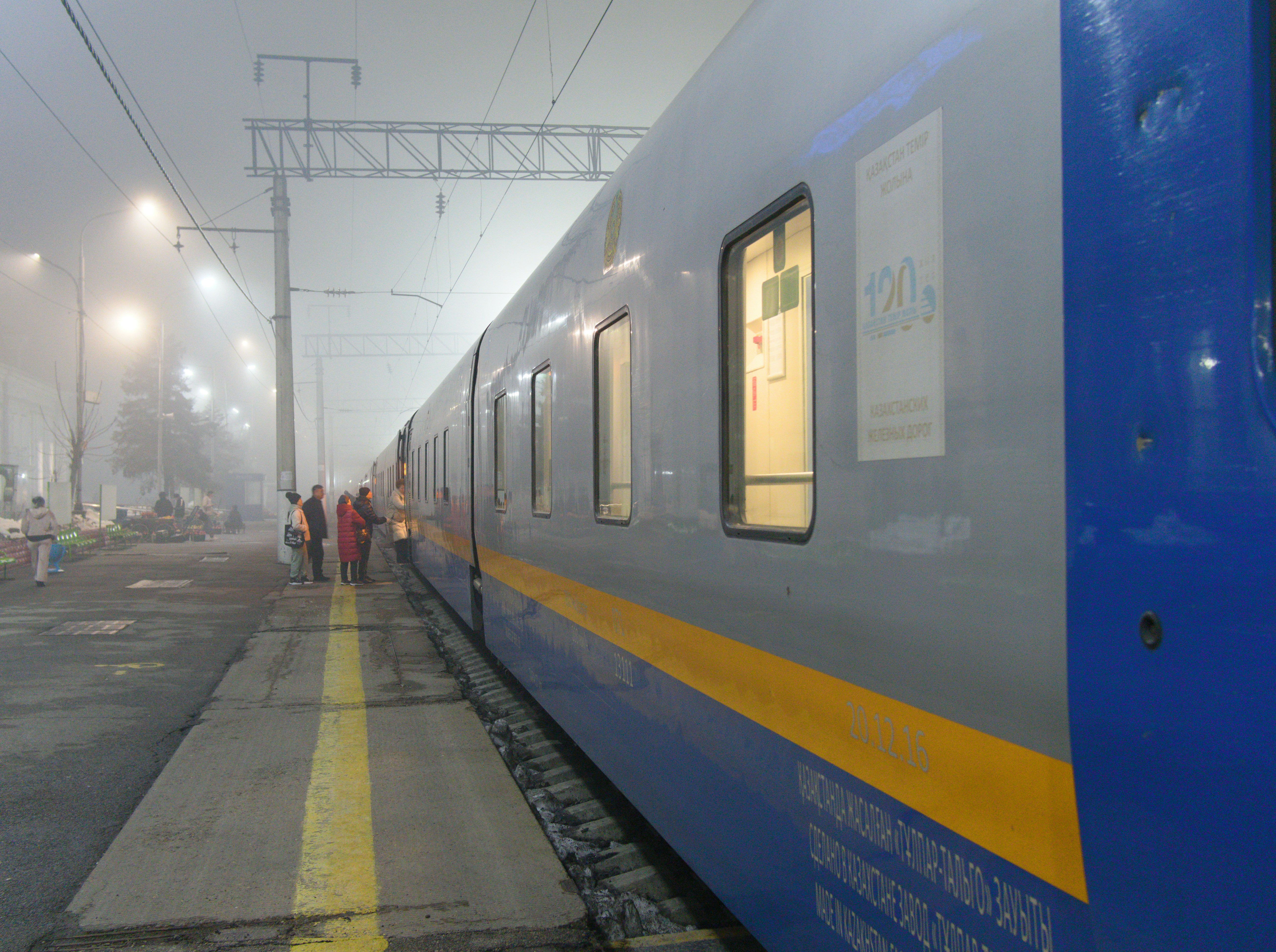 Foggy Platform Evening: A Blue Train Carries Passengers into the Unknown