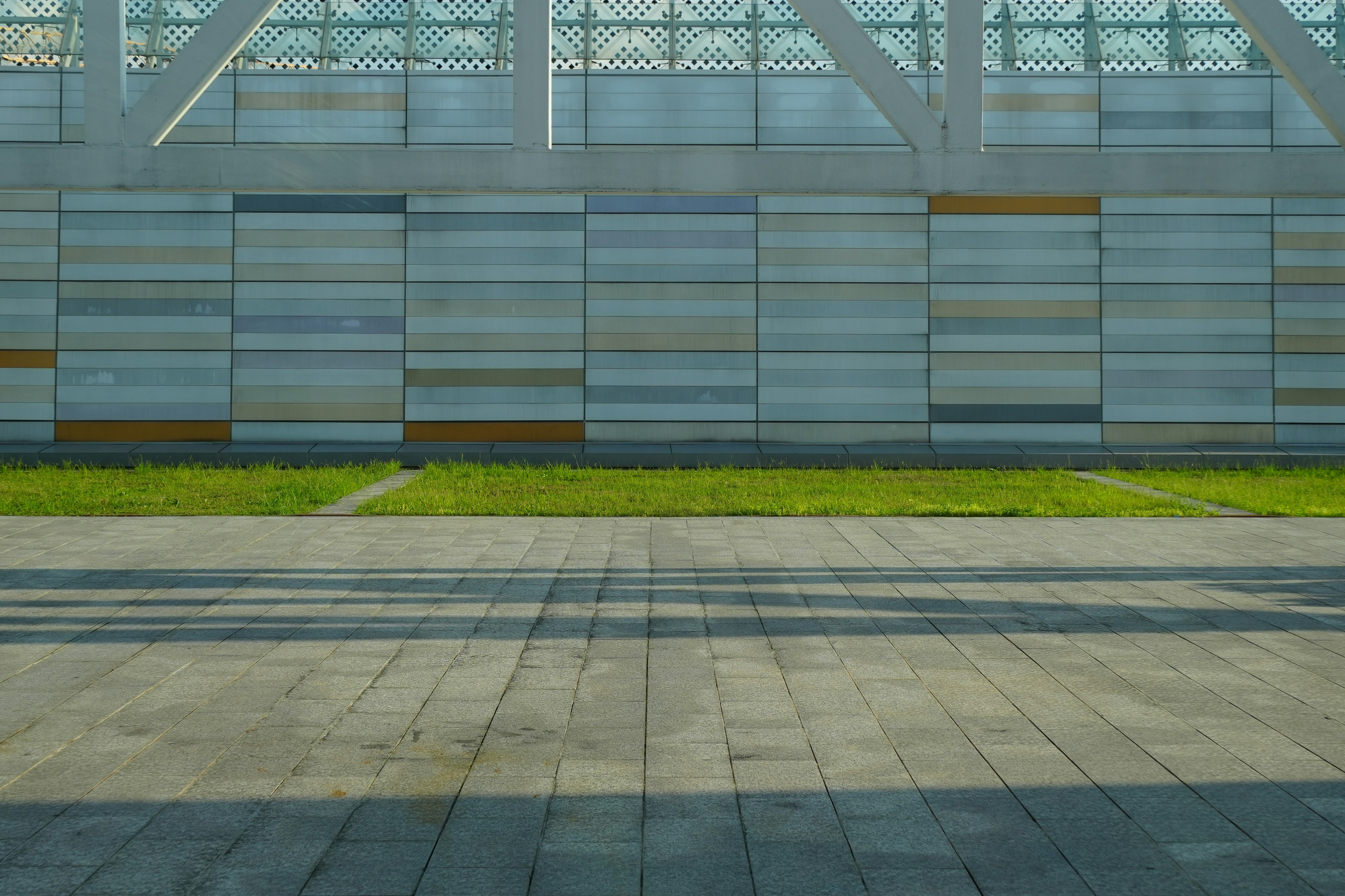 Patterned Glass Wall Above a Quiet Green Strip