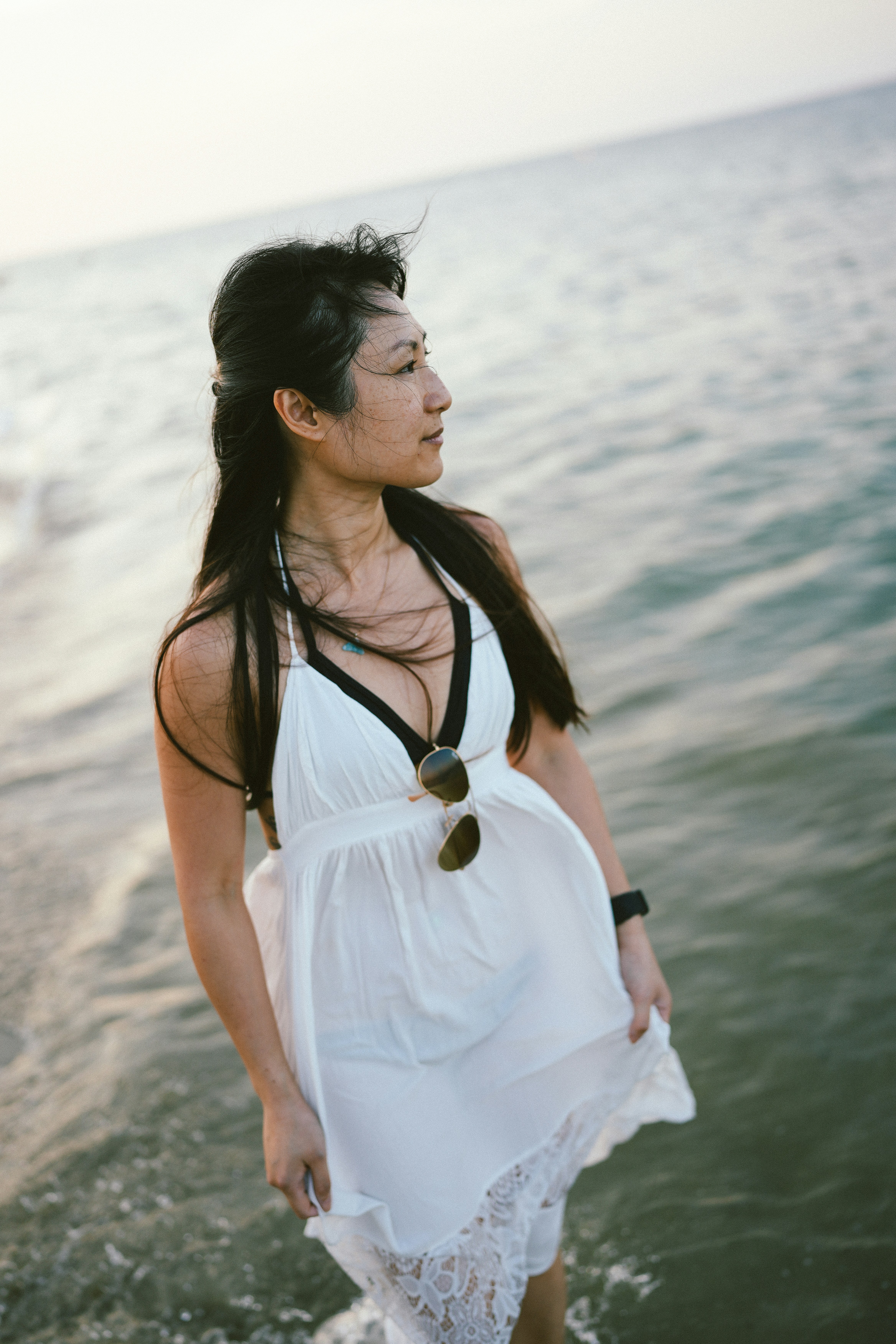 Sunlit Embrace by the Sea: White Dress Against Ocean Breeze